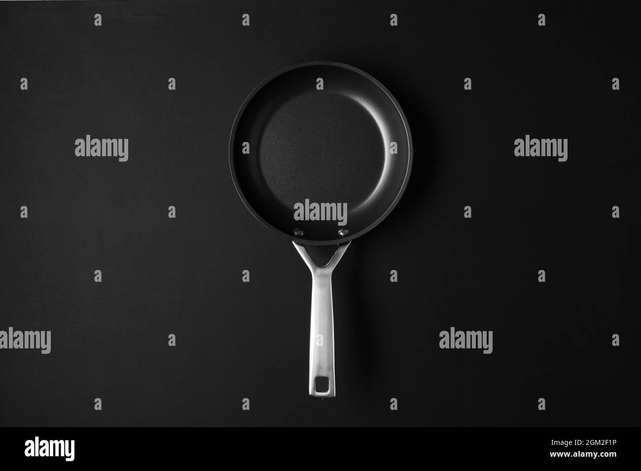 Empty black frying pan on black wooden table background. Overhead top ...