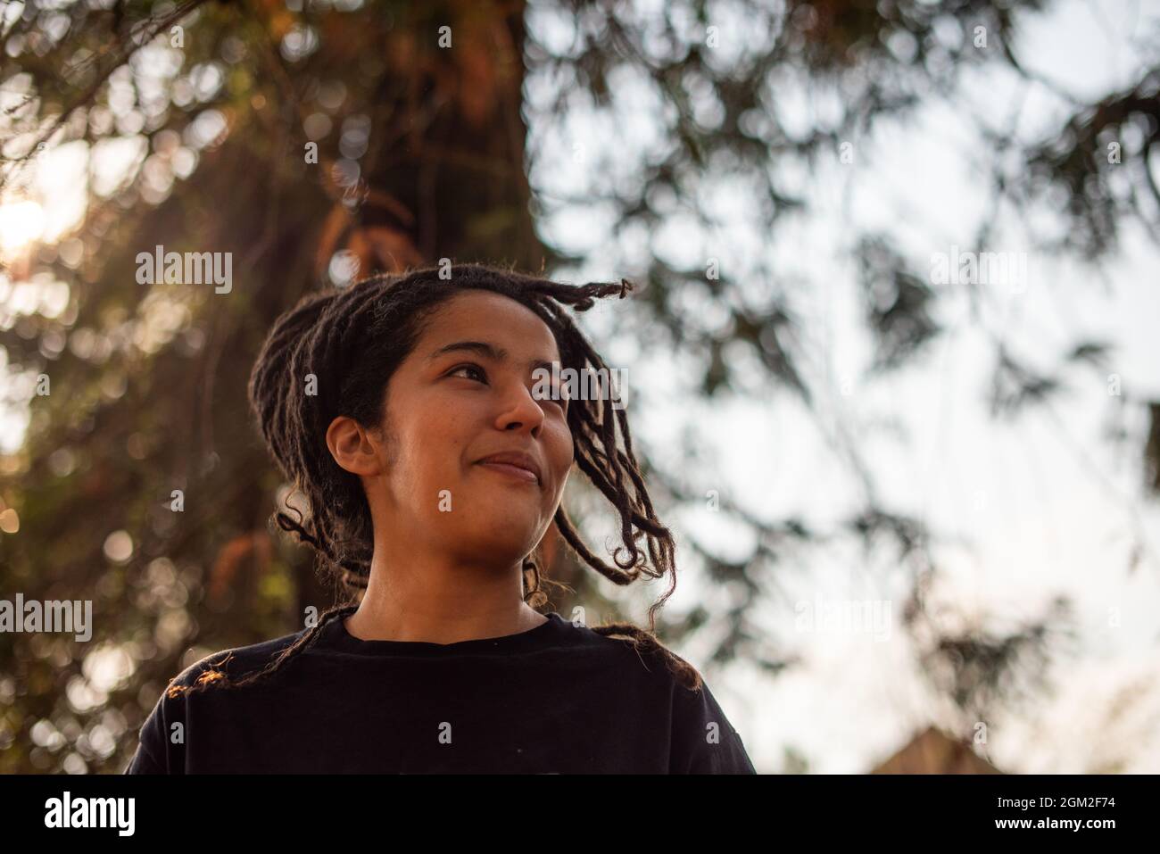 Woman seen standing under tree with sunlight reflecting through ...