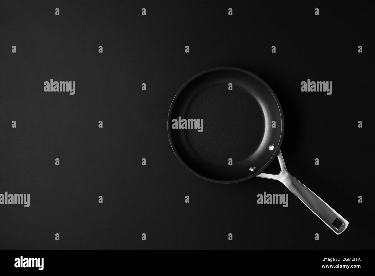 Empty black frying pan on black wooden table background. Overhead top ...