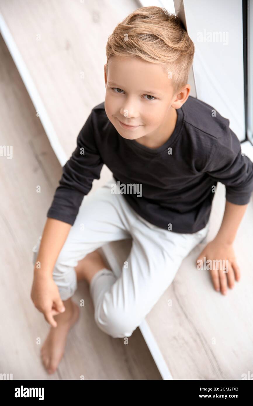 Cute little boy sitting near window at home Stock Photo - Alamy