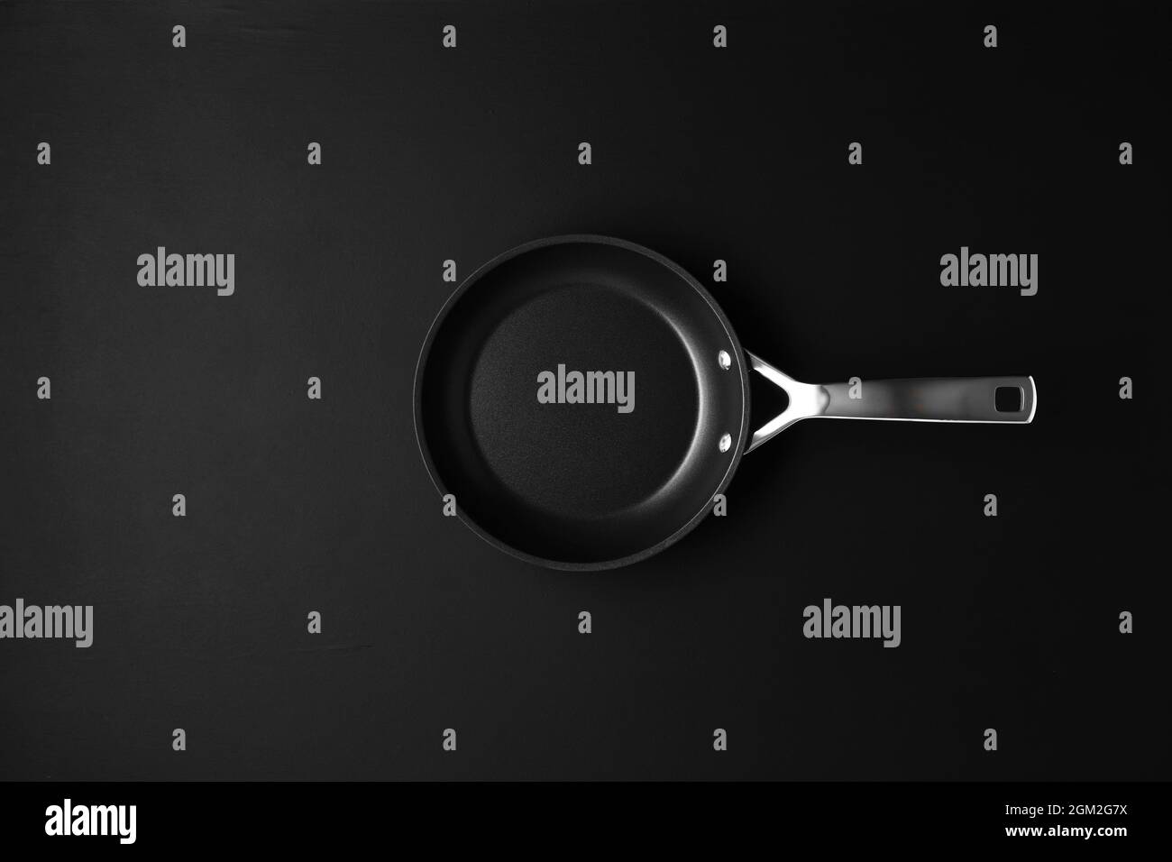 Empty black frying pan on black wooden table background. Overhead top ...