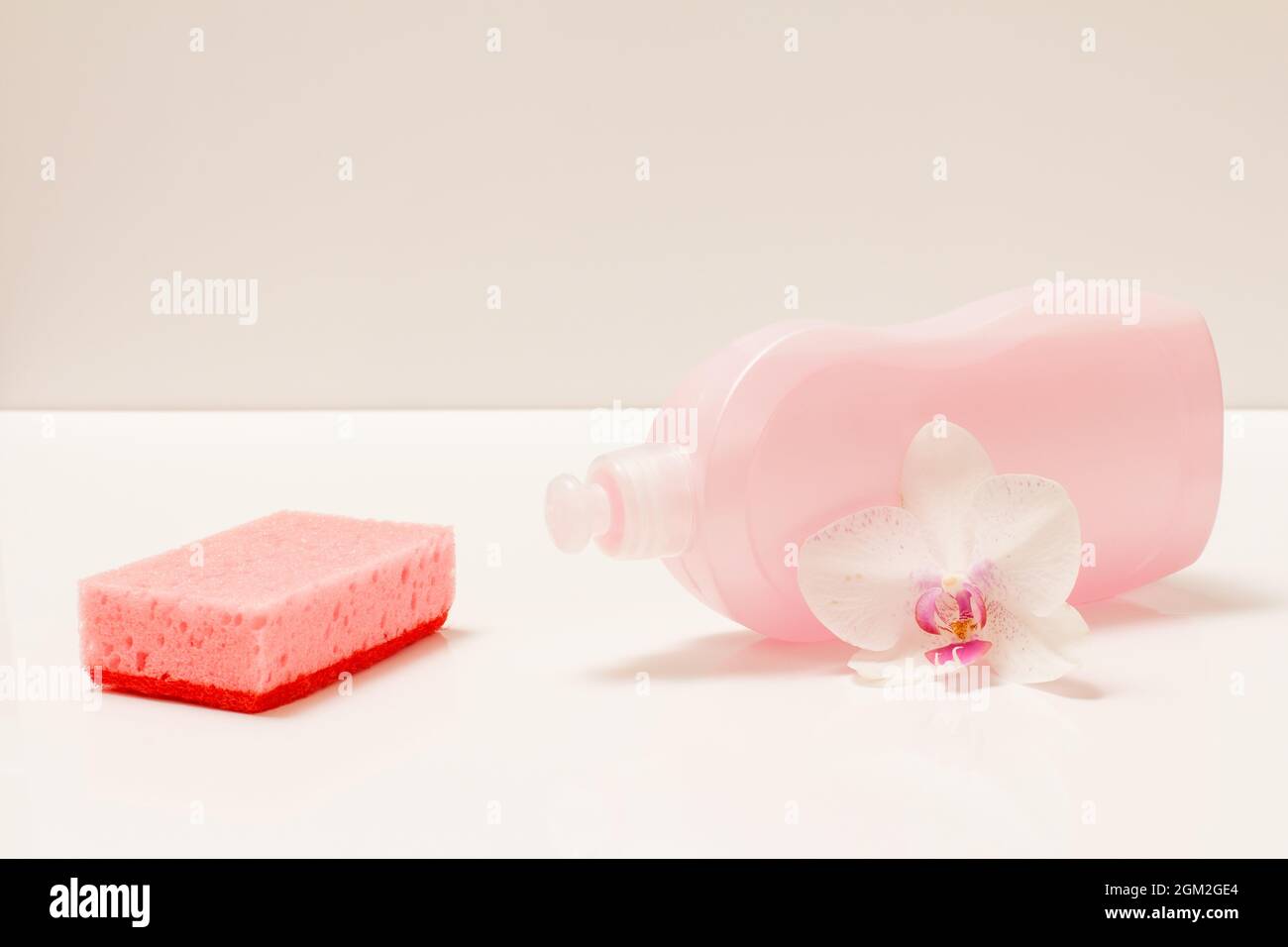 Bottle of dishwashing liquid, a sponge and a bud of orchid flower on ...
