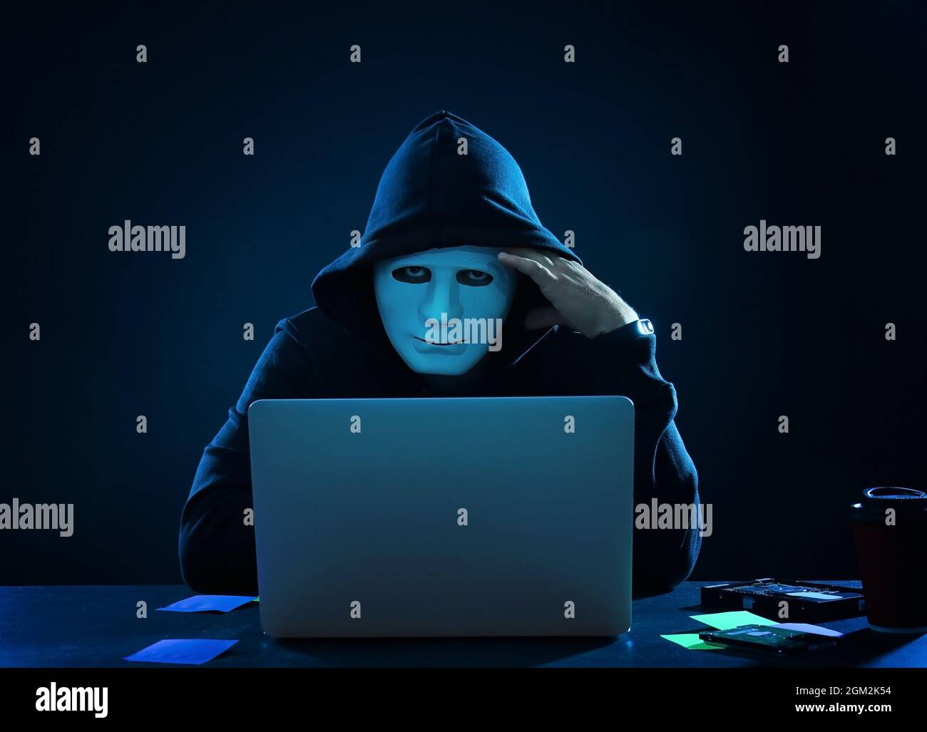 Hacker in mask using laptop in dark room Stock Photo - Alamy