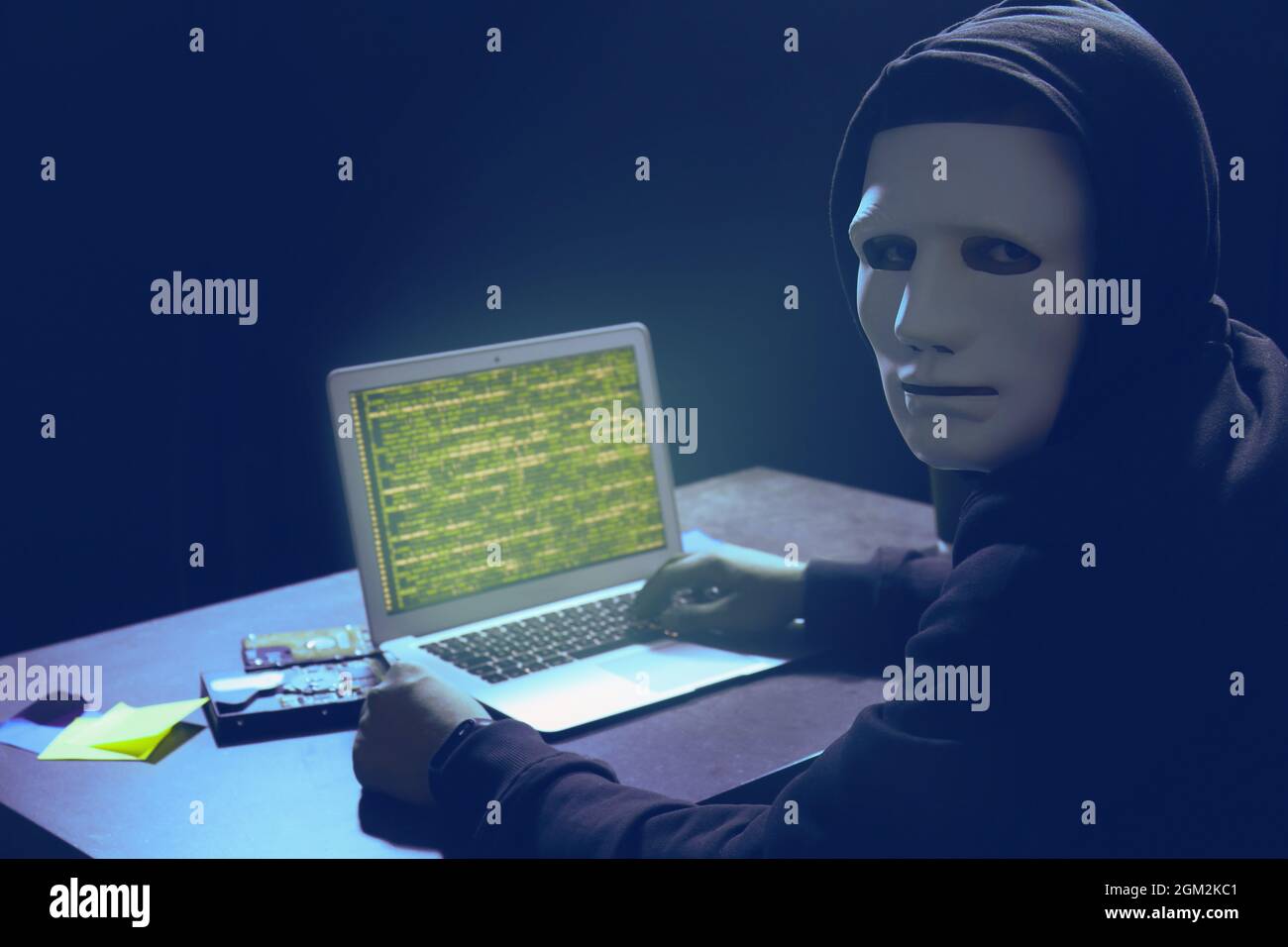 Hacker in mask using laptop in dark room Stock Photo - Alamy