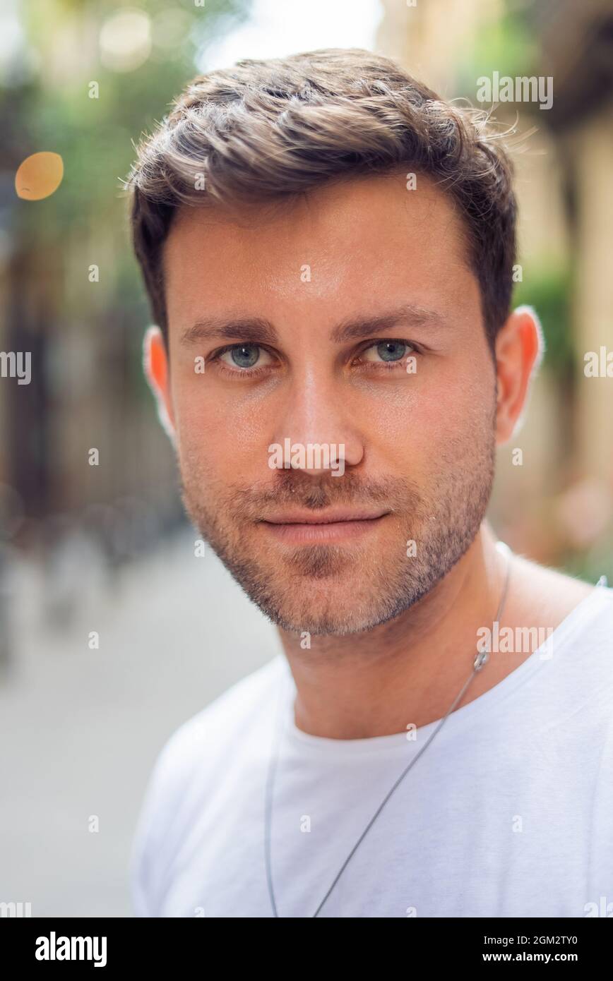Modern young guy with stylish haircut and beard looking at camera ...