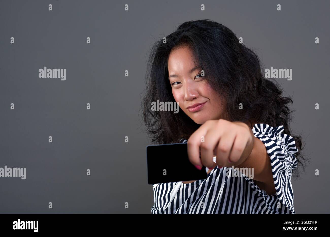 Young Chinese brunette offering card with direct and defiant gaze Stock ...