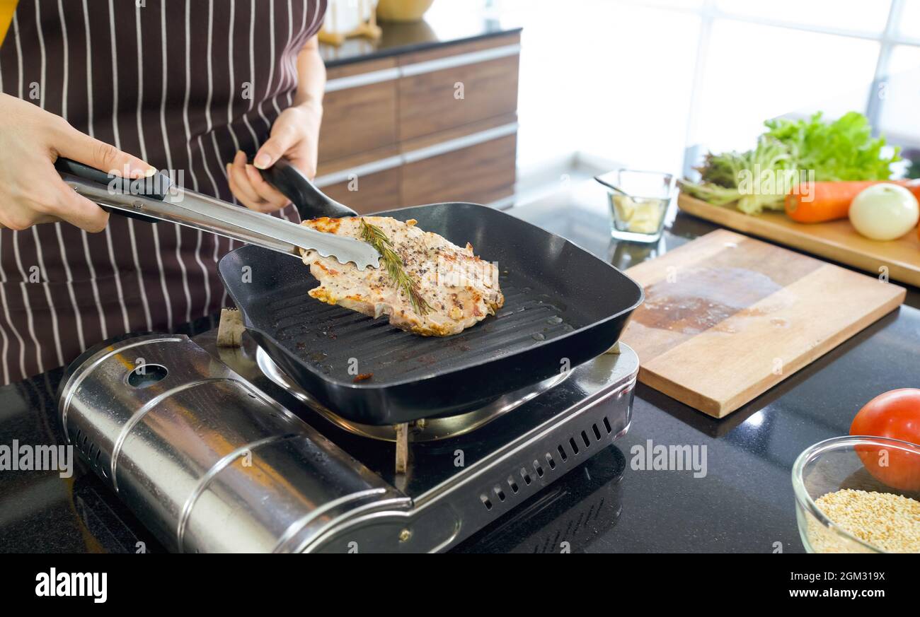 Chef uses tongs to tong the steak from the hot pan. The wooden chop ...
