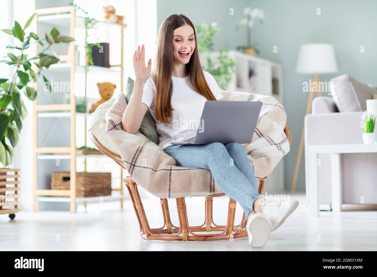 Portrait of attractive cheerful girl sitting in chair using laptop ...