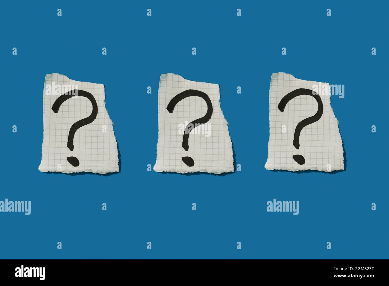 three question marks in three pieces of paper arranged in a line on a ...