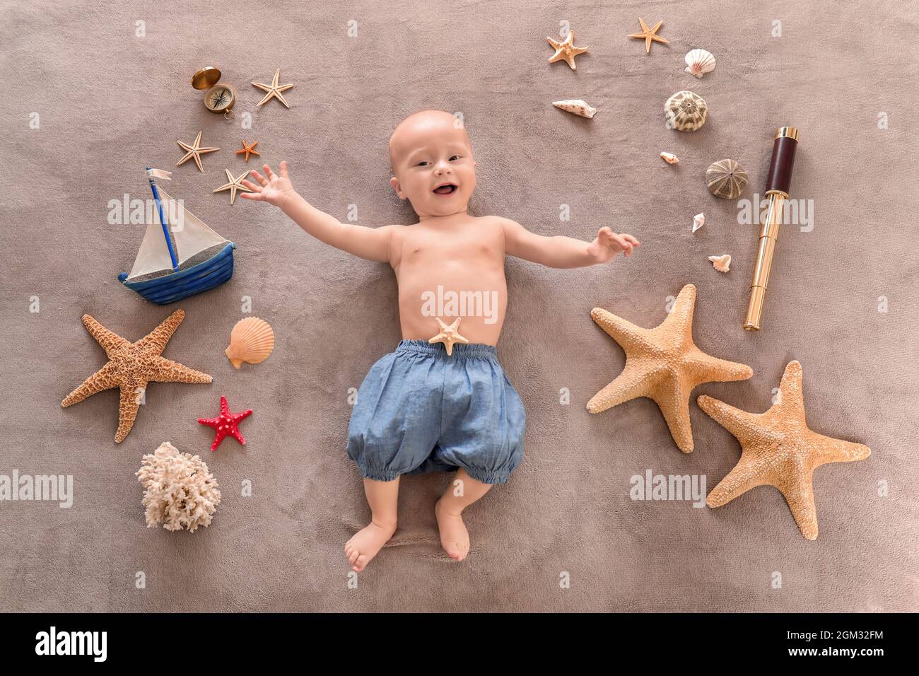 Cute boy with shells on textile background Stock Photo - Alamy