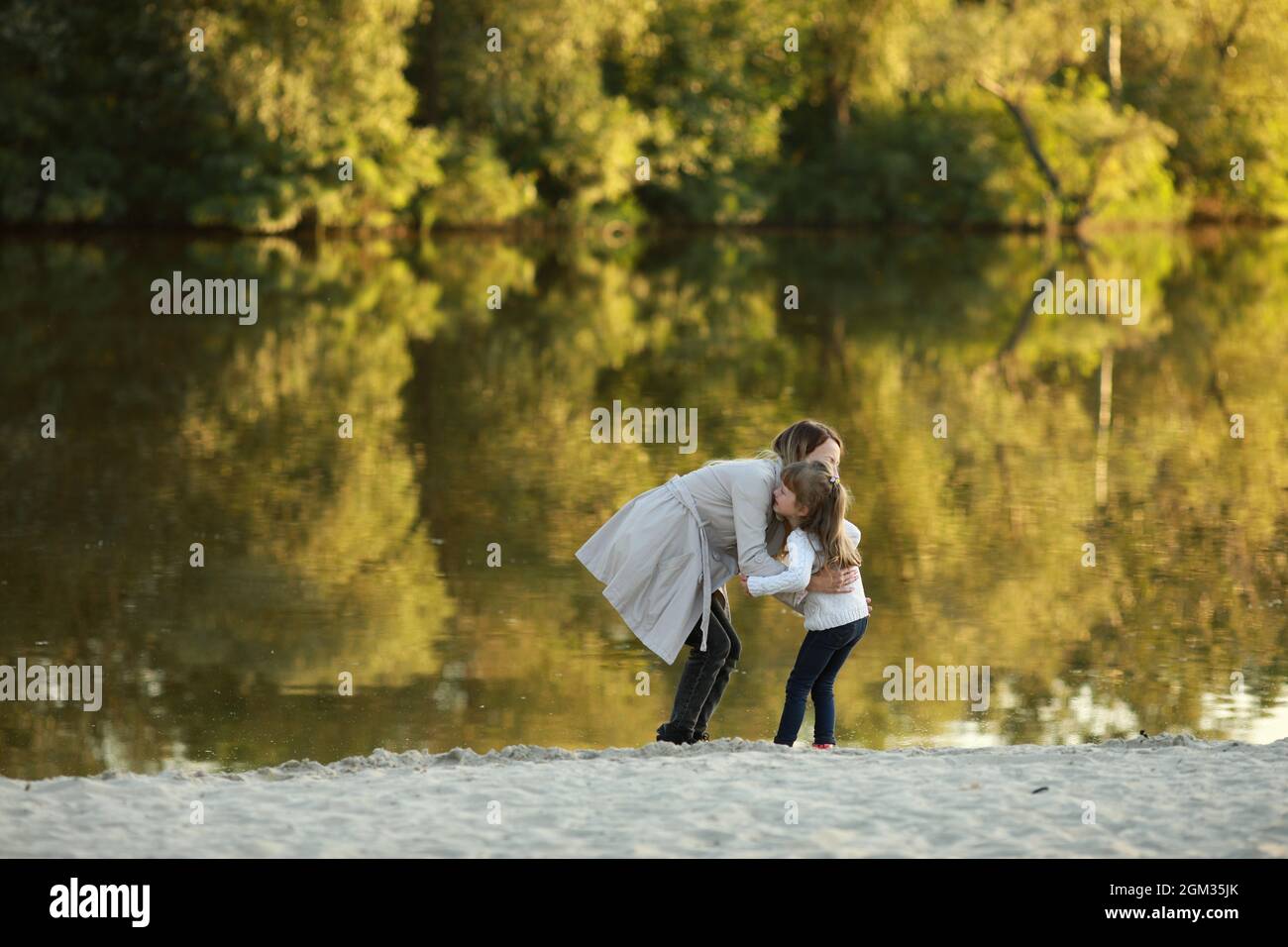 Mother comforts her crying capricious daughter while the walk on beach ...