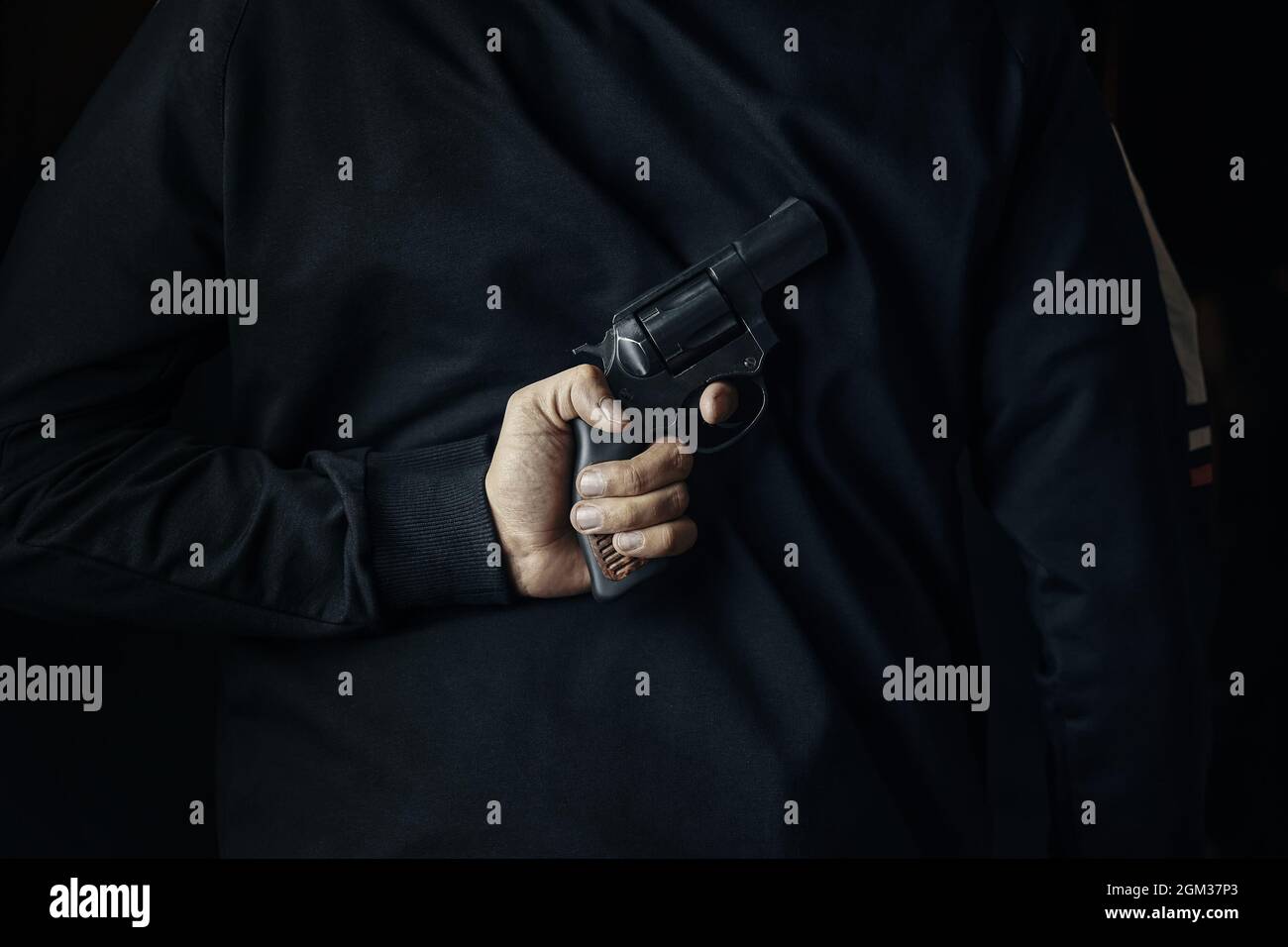 Man hiding revolver behind back hi-res stock photography and images - Alamy