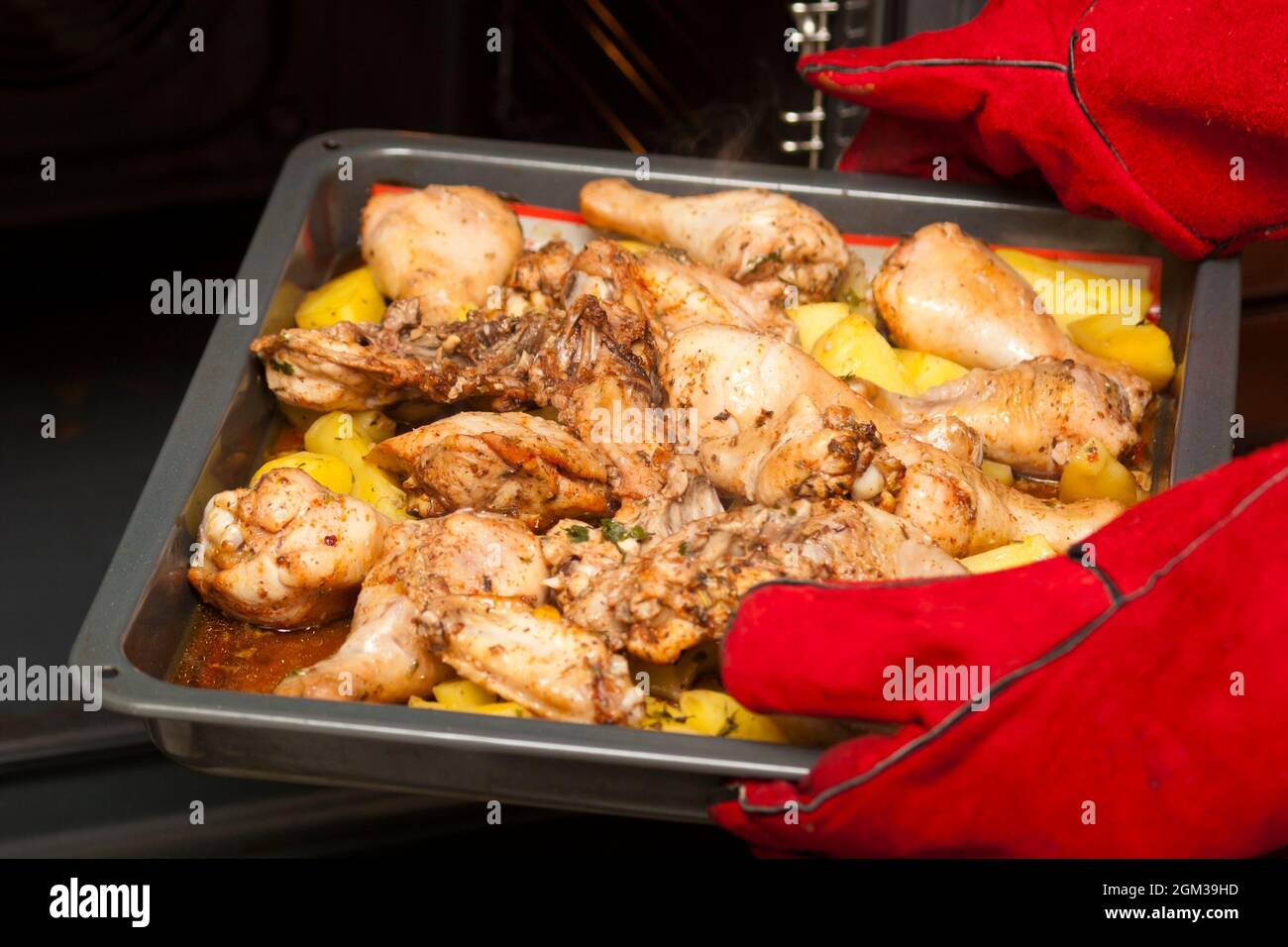 Cooking chicken meat with potatoes in the oven Stock Photo - Alamy