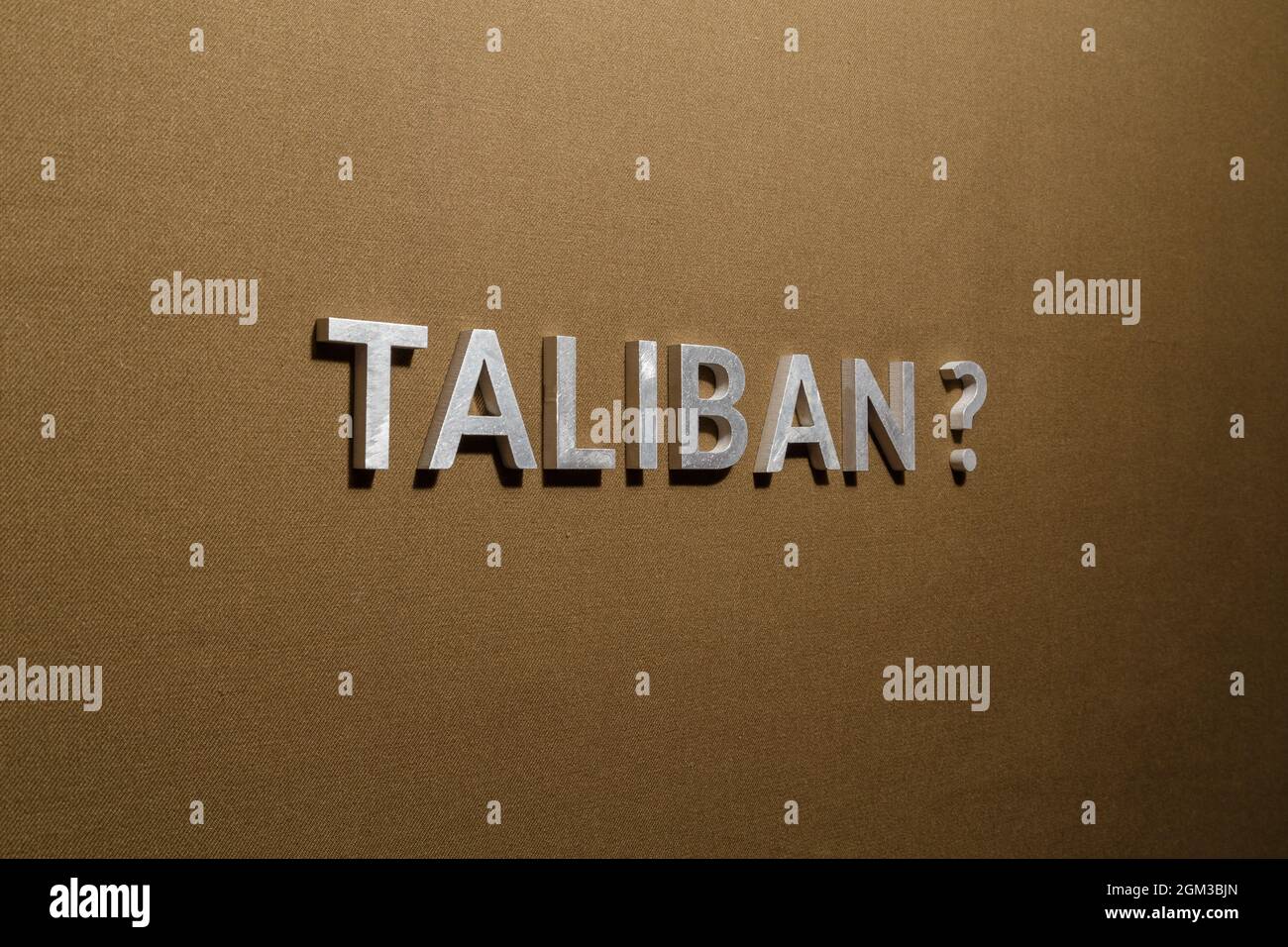 the question taliban laid with silver metal letters on rough tan khaki ...