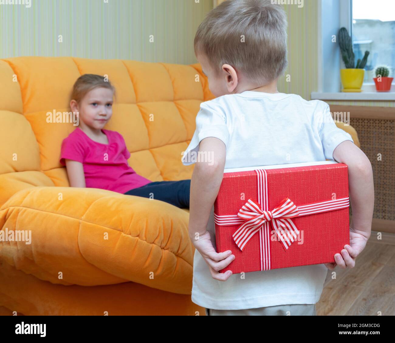 The moment of waiting for a gift. The boy is holding a red gift box ...