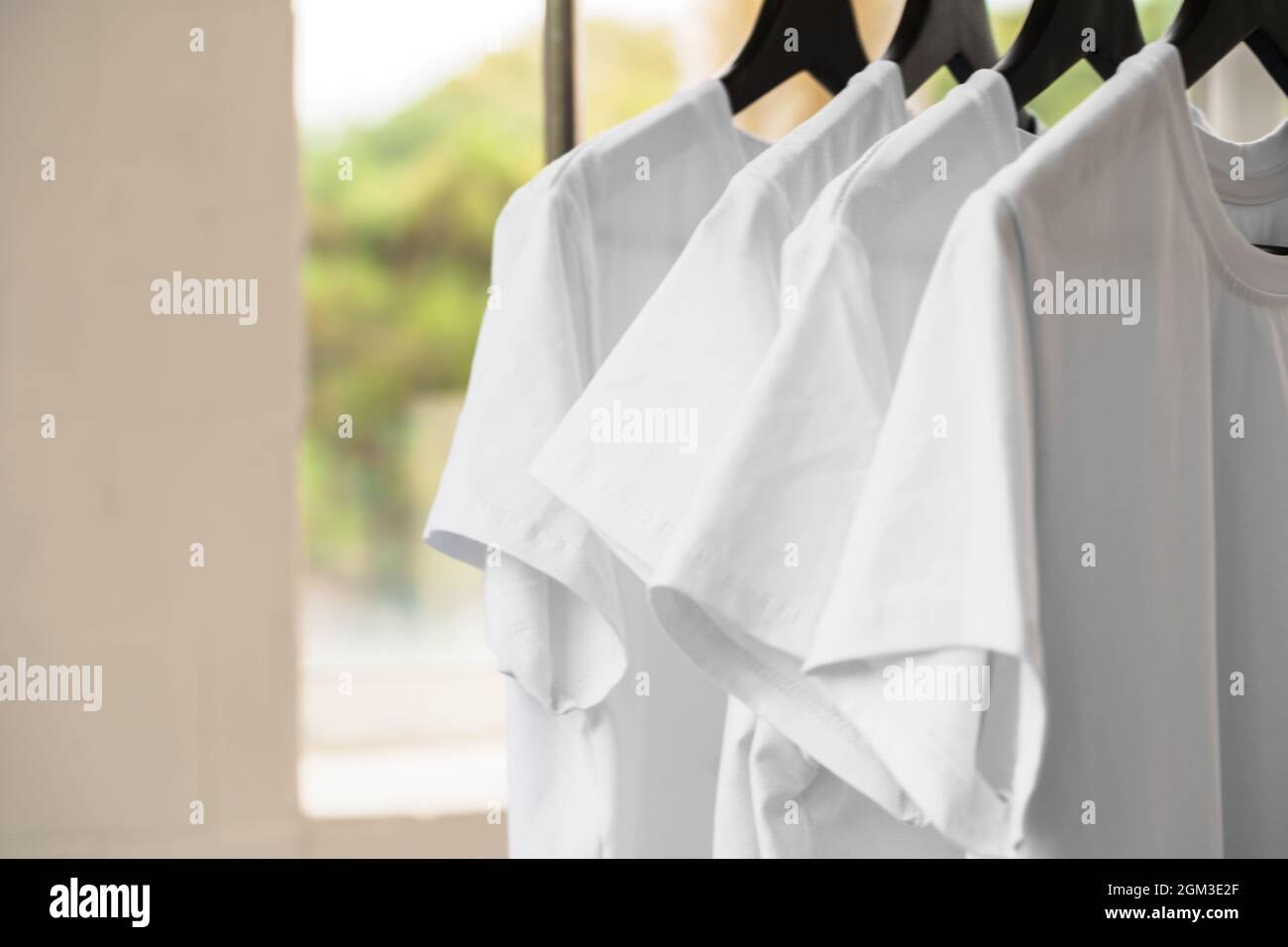 Row of white t-shirts on hangers on rack Stock Photo - Alamy