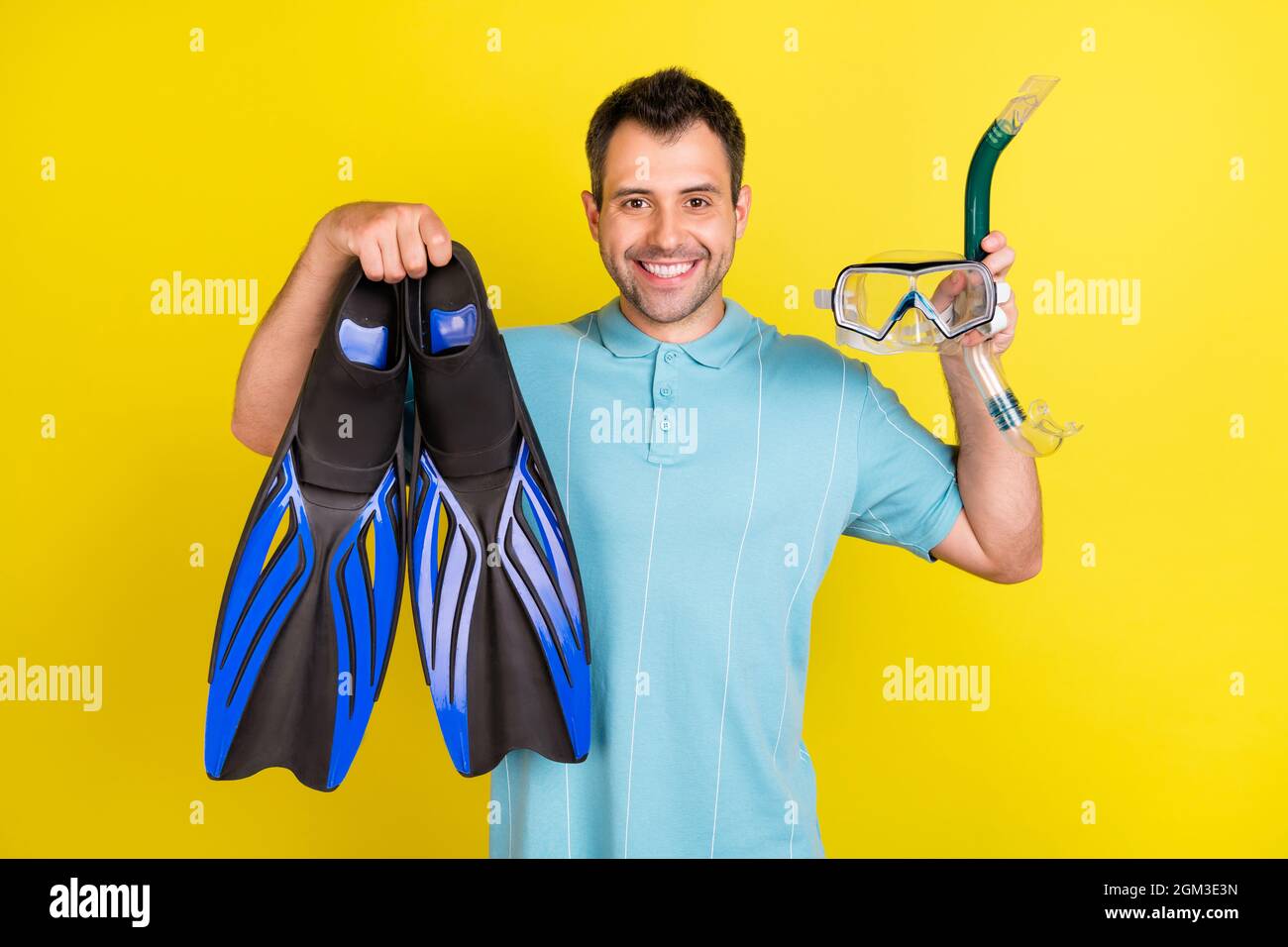 Photo of cool brunet man hold flippers mask wear blue t-shirt isolated ...