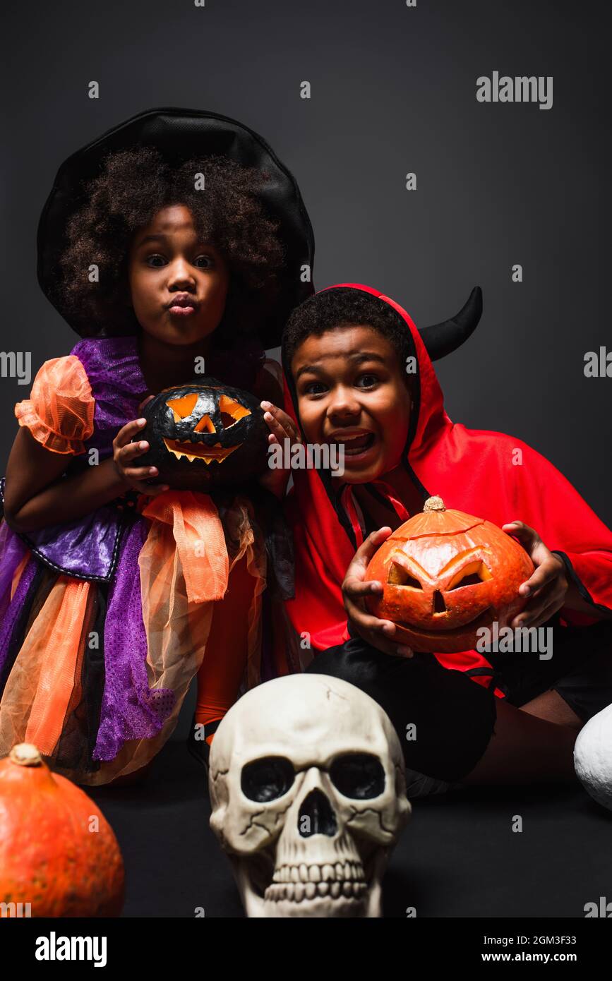 african american siblings in costumes holding creepy halloween pumpkins ...