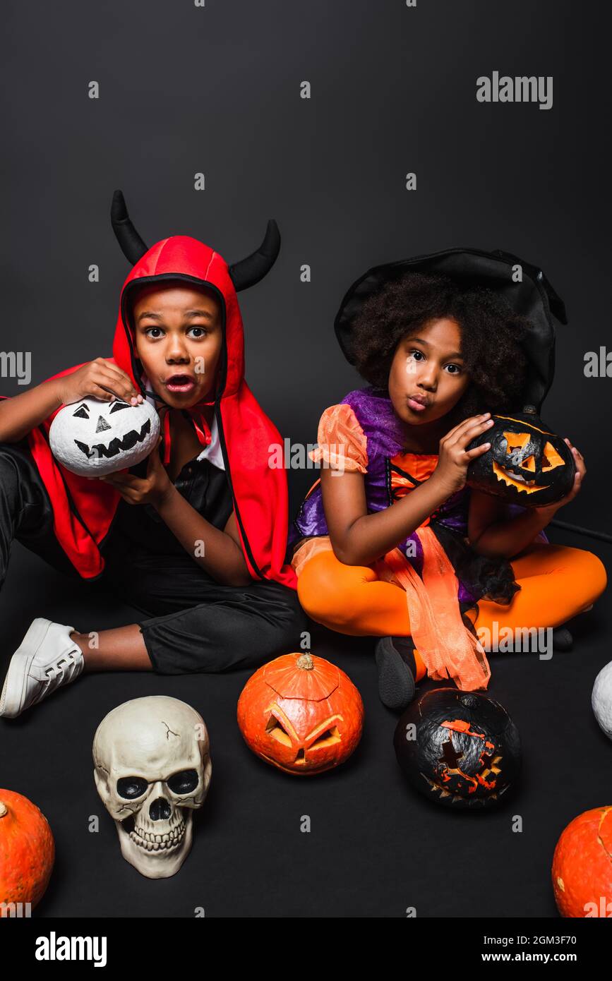 spooky african american children in halloween costumes holding skull ...