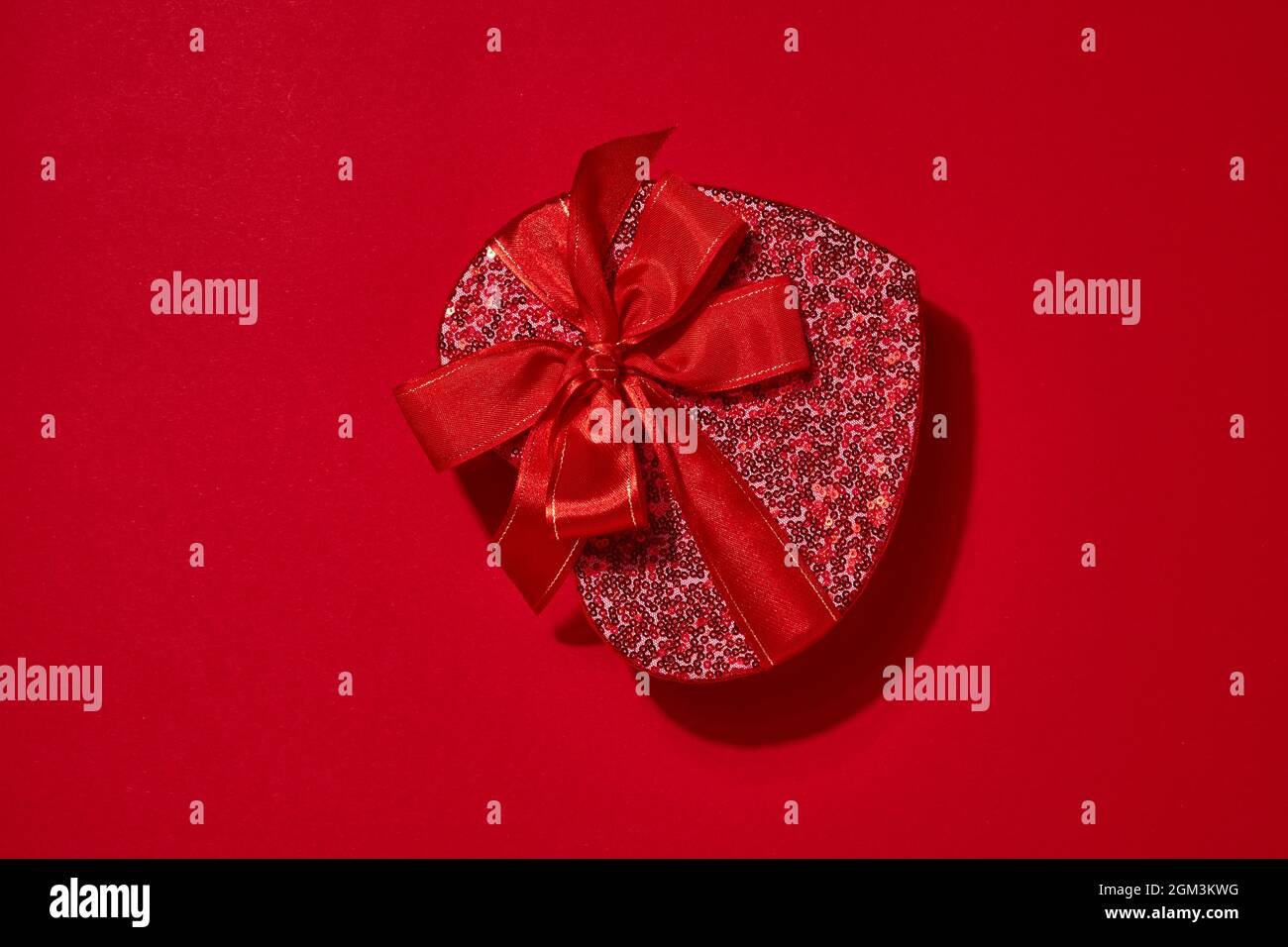Open red heart box, ribbon and scattered hearts nearbyon scarlet ...