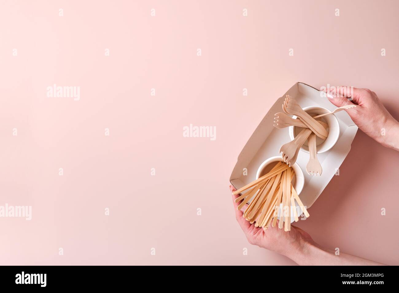 Female hand takes cocktail straws, paper cups, dishes, wooden forks ...