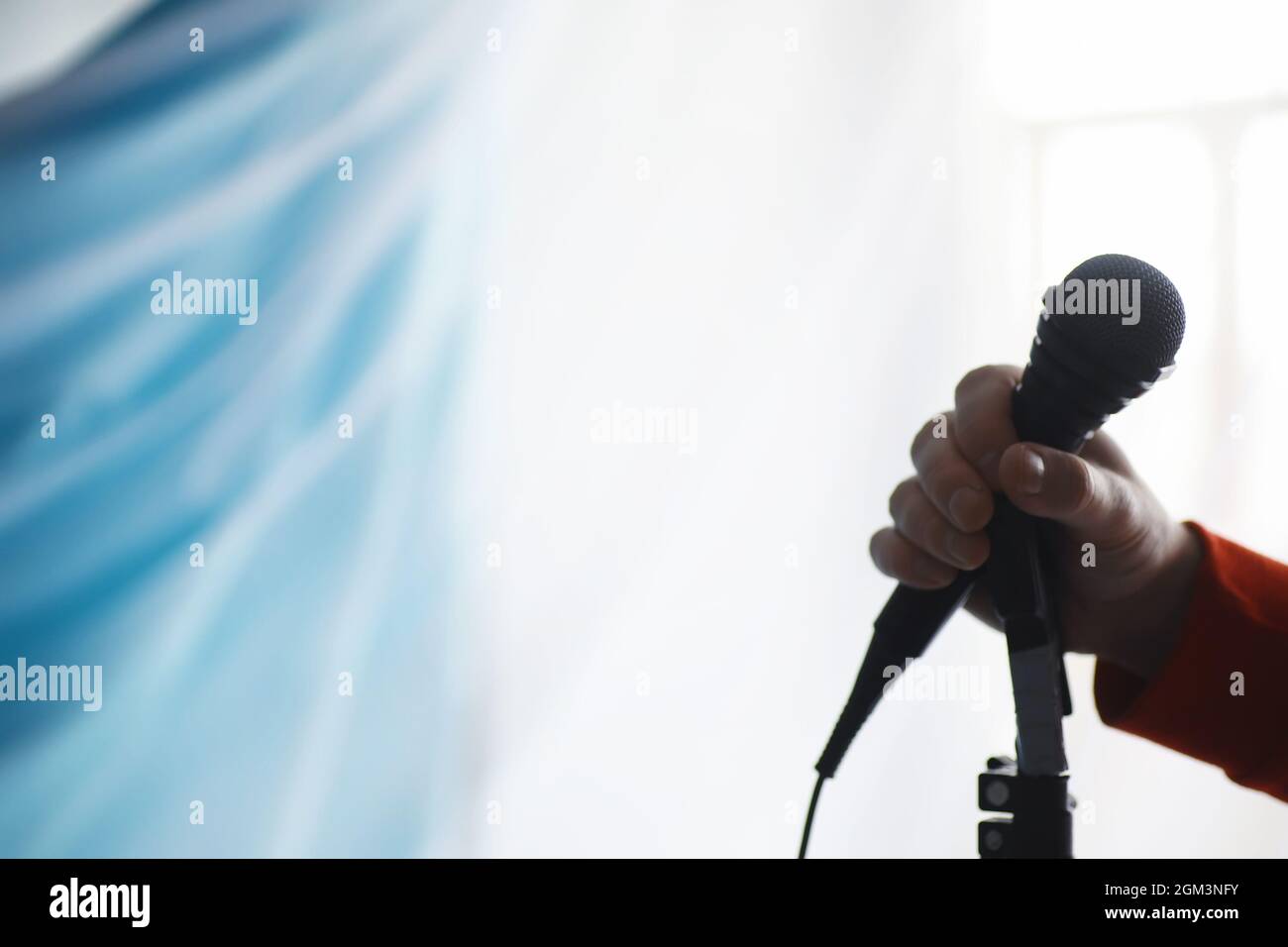 Stand with a microphone. Man holds hands a microphone on tripod ...