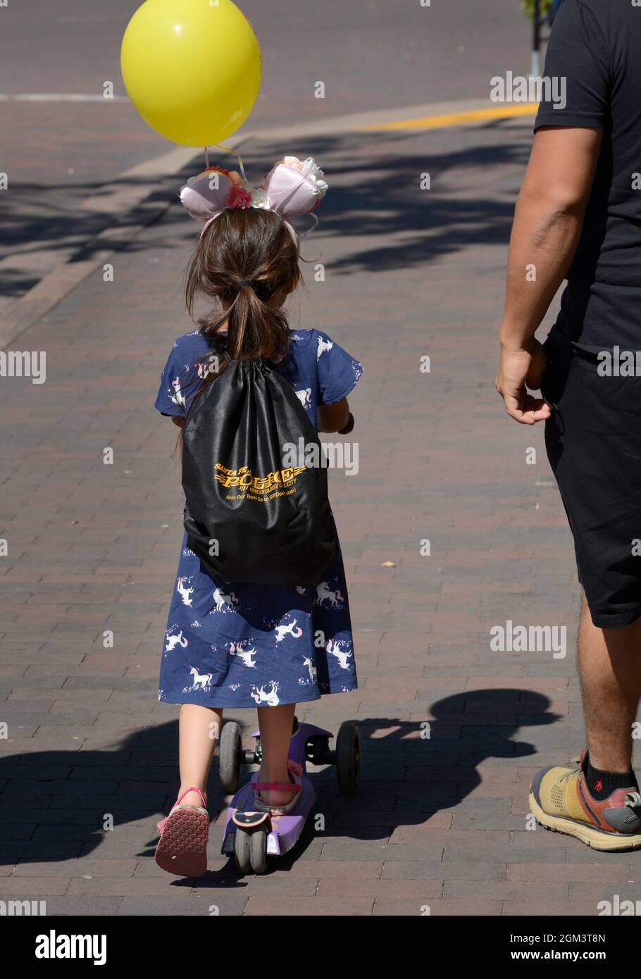 A young girls rides a scooter along a bricked street during an outdoor ...