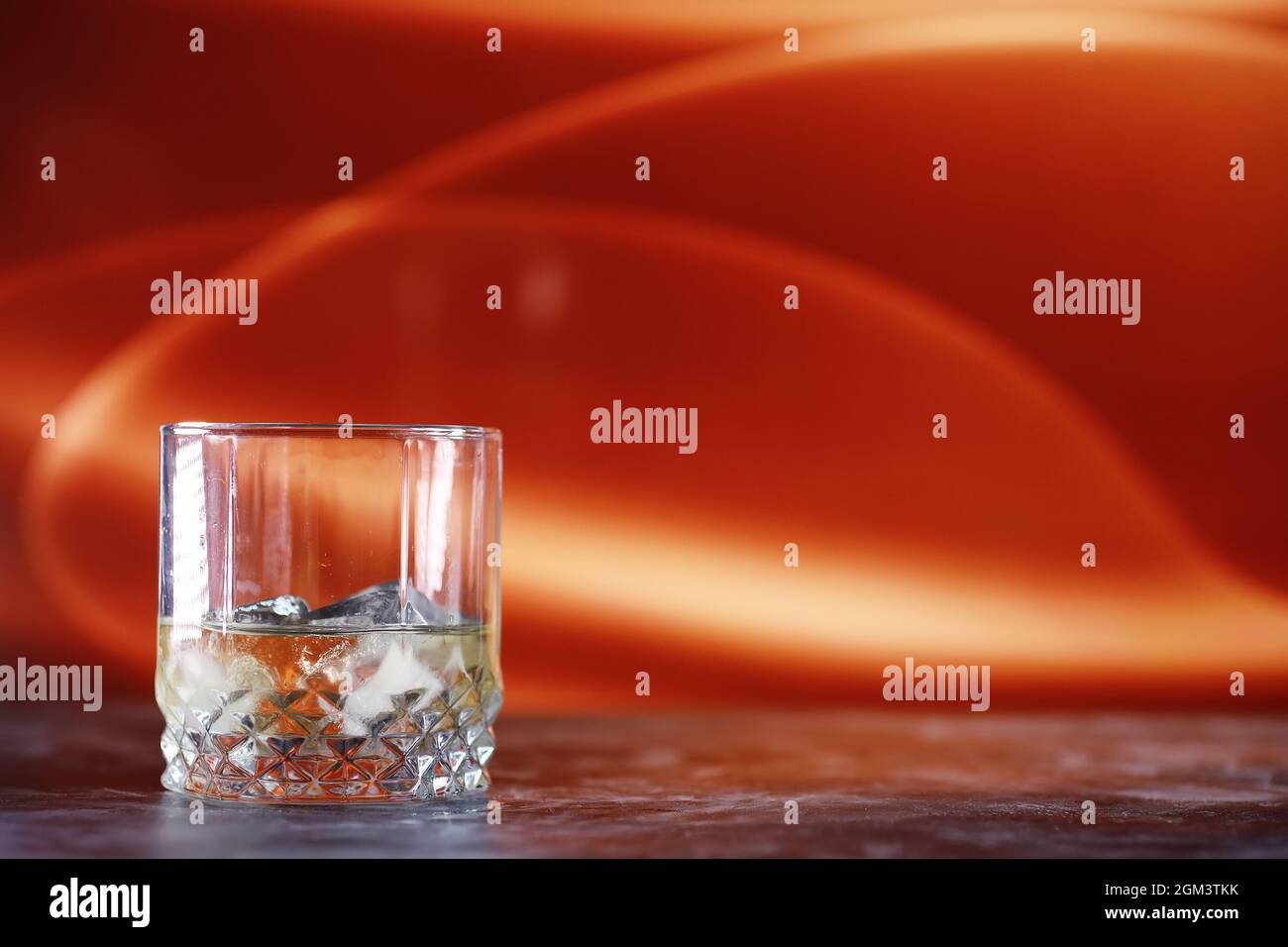 A glass of hard alcohol with ice on a bar counter. Whiskey with soda in ...