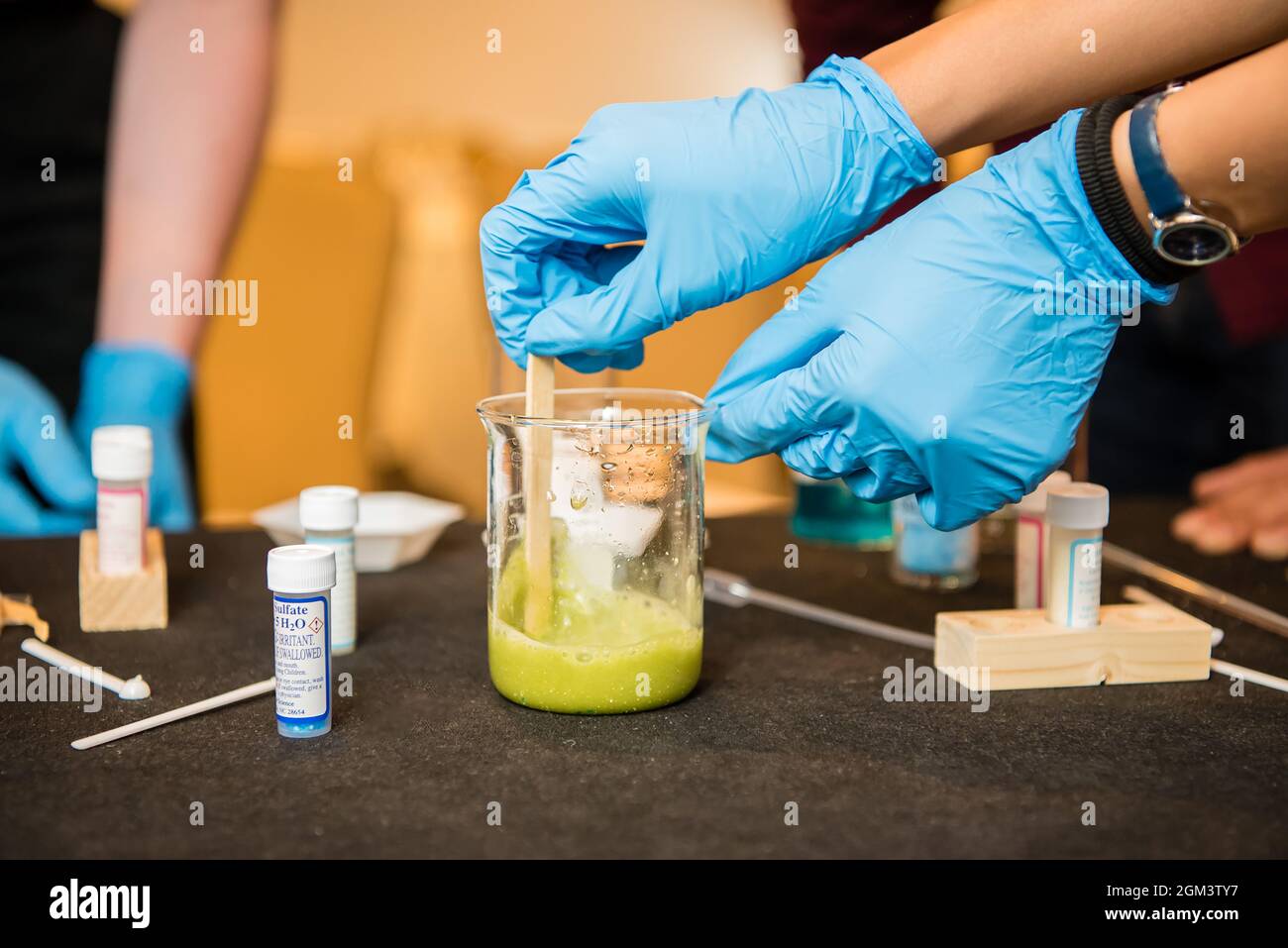 Latex gloved hand pour a beaker of liquid during a science experiment ...