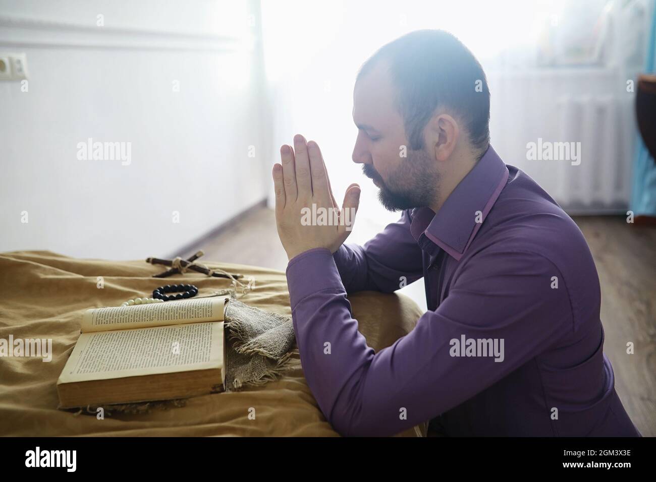 Man reading and pray from the holy bible near the bed in evening ...