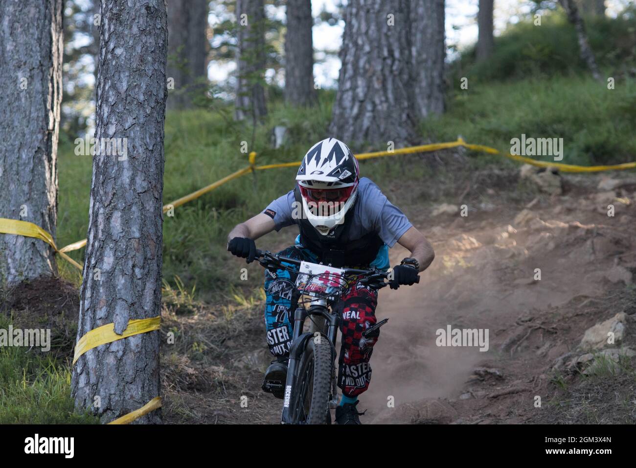 A downhill mountain biker descending on a difficult terrain in woods ...
