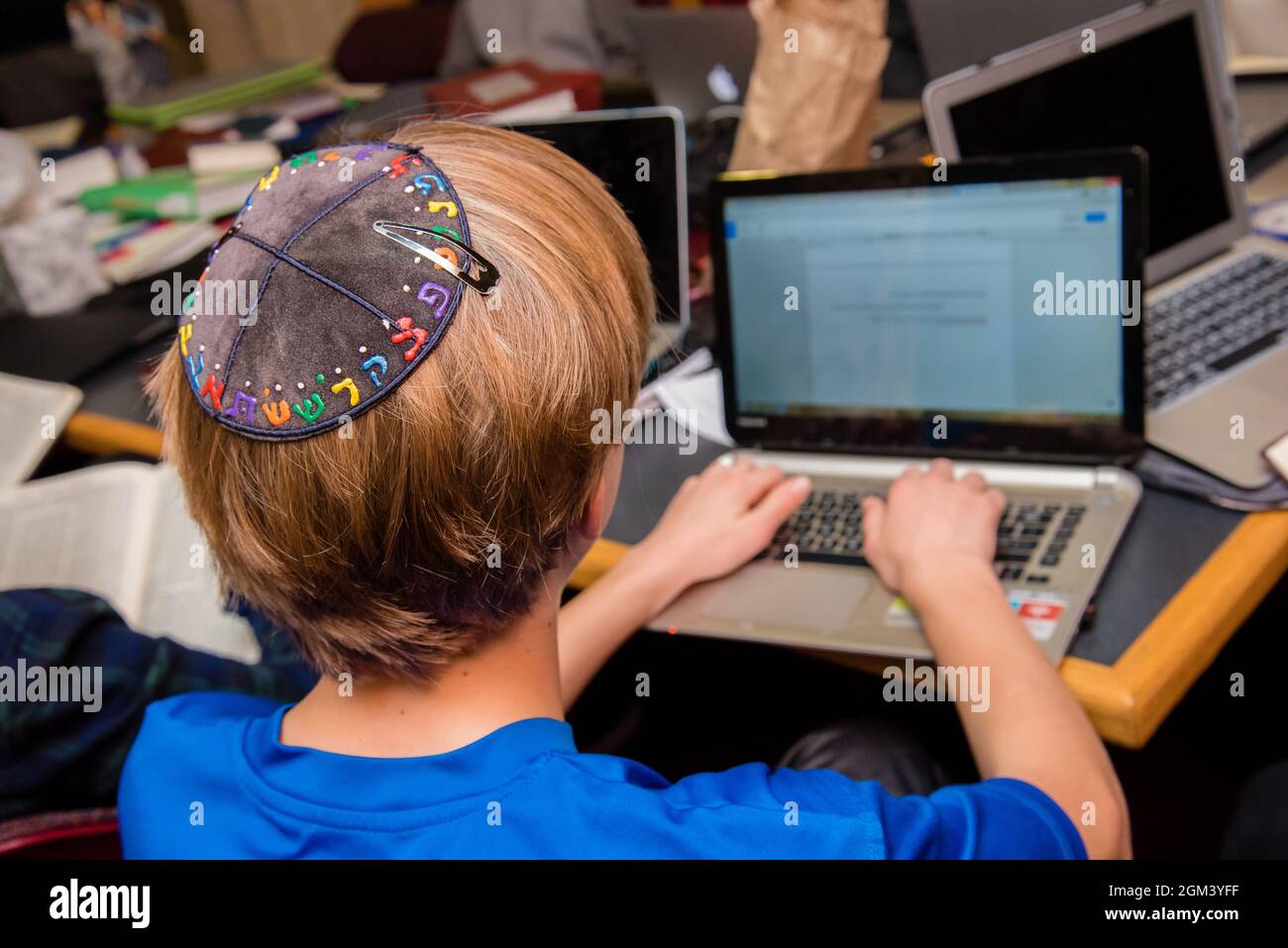 Jewish boy wearing yarmulke from the back sitting in a classroom ...