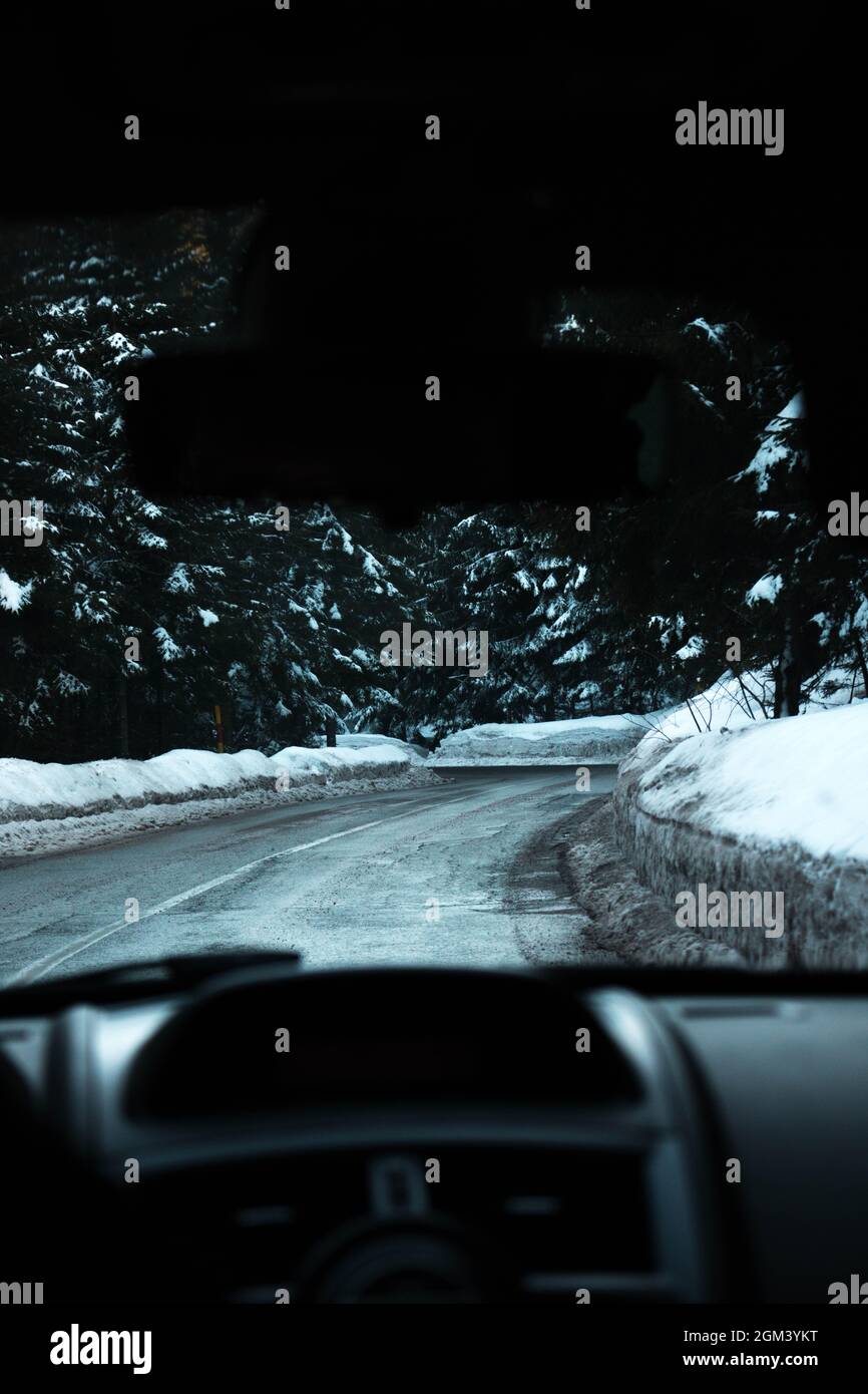 A winter car road with snow on the sides from the inside of a car cabin ...