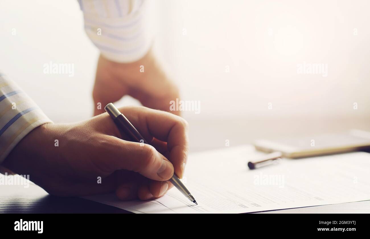 Business meeting. A man signs a contract. Male hand with pen makes ...
