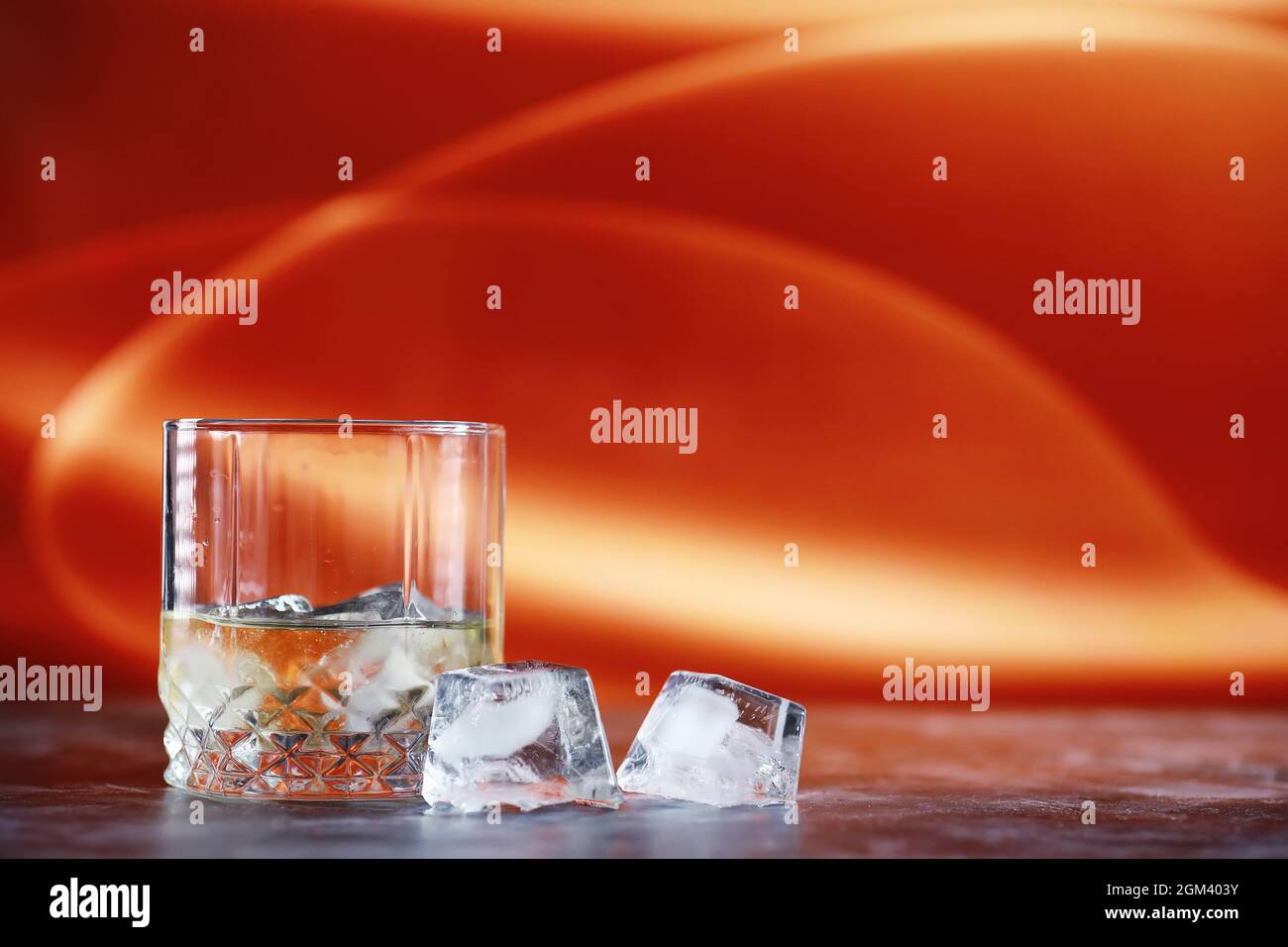 A glass of hard alcohol with ice on a bar counter. Whiskey with soda in ...