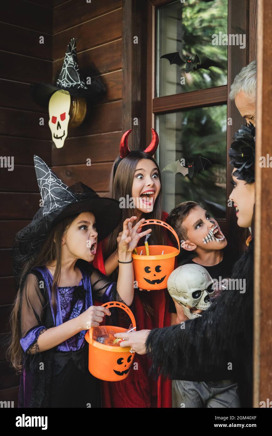 kids in halloween costumes growling at parents on cottage porch with ...