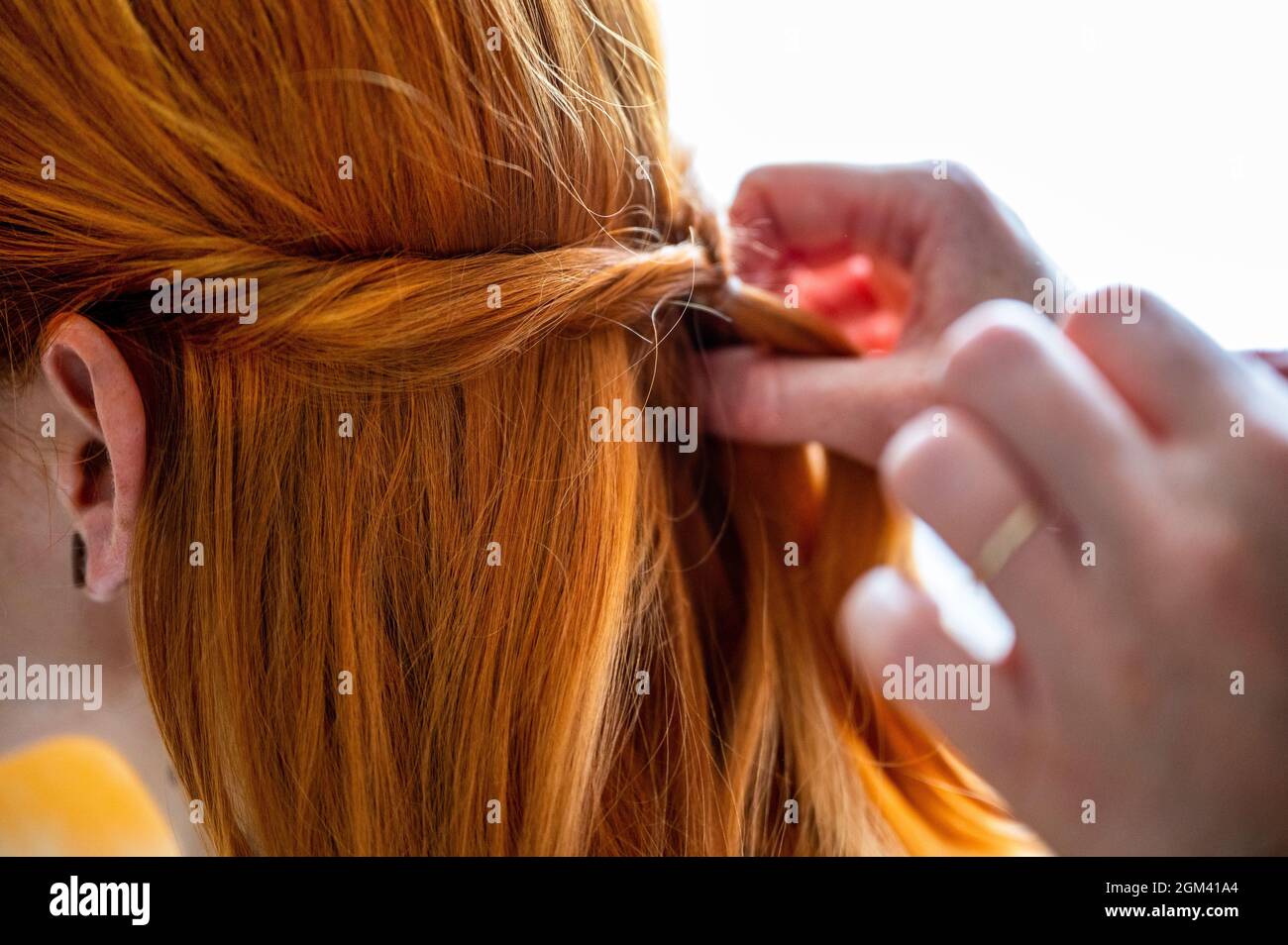 Hairdresser's hand braiding woman's red long hair in beauty salon Stock ...