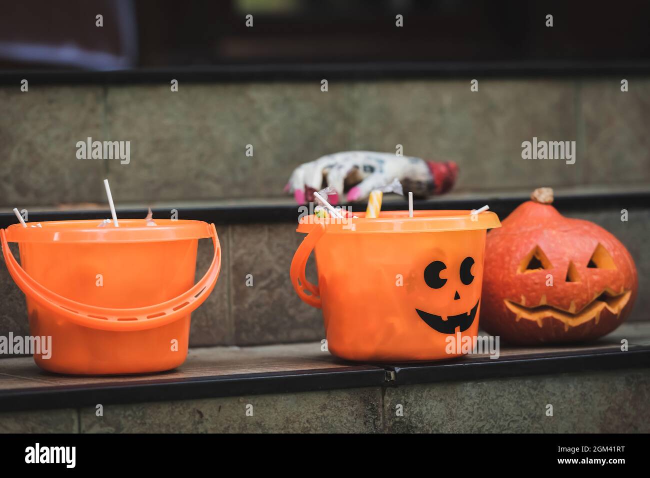 halloween buckets with sweets near carved pumpkin and blurred toy hand ...
