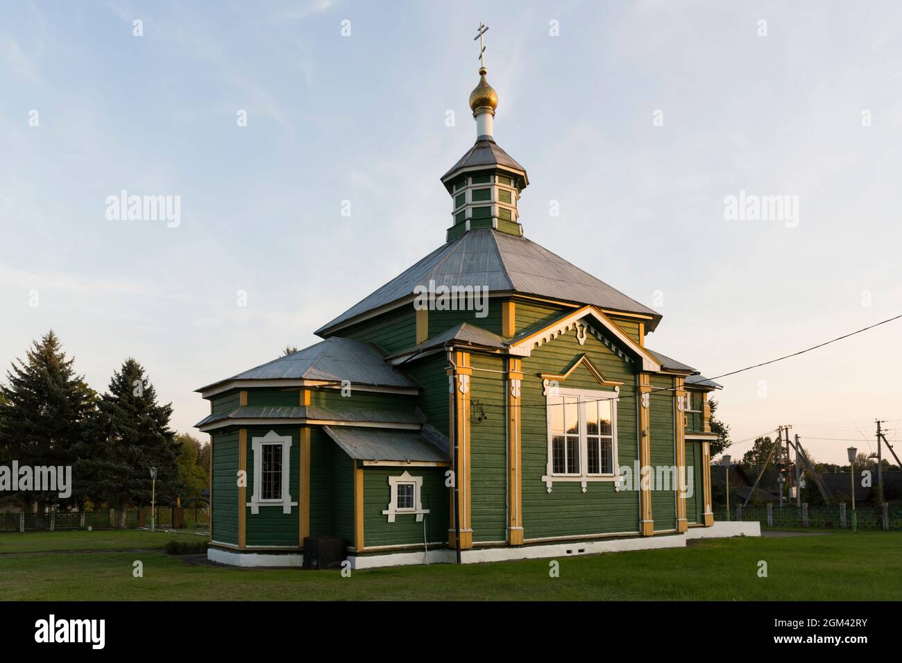 An old wooden 19th century church in green with a gold dome and gold ...