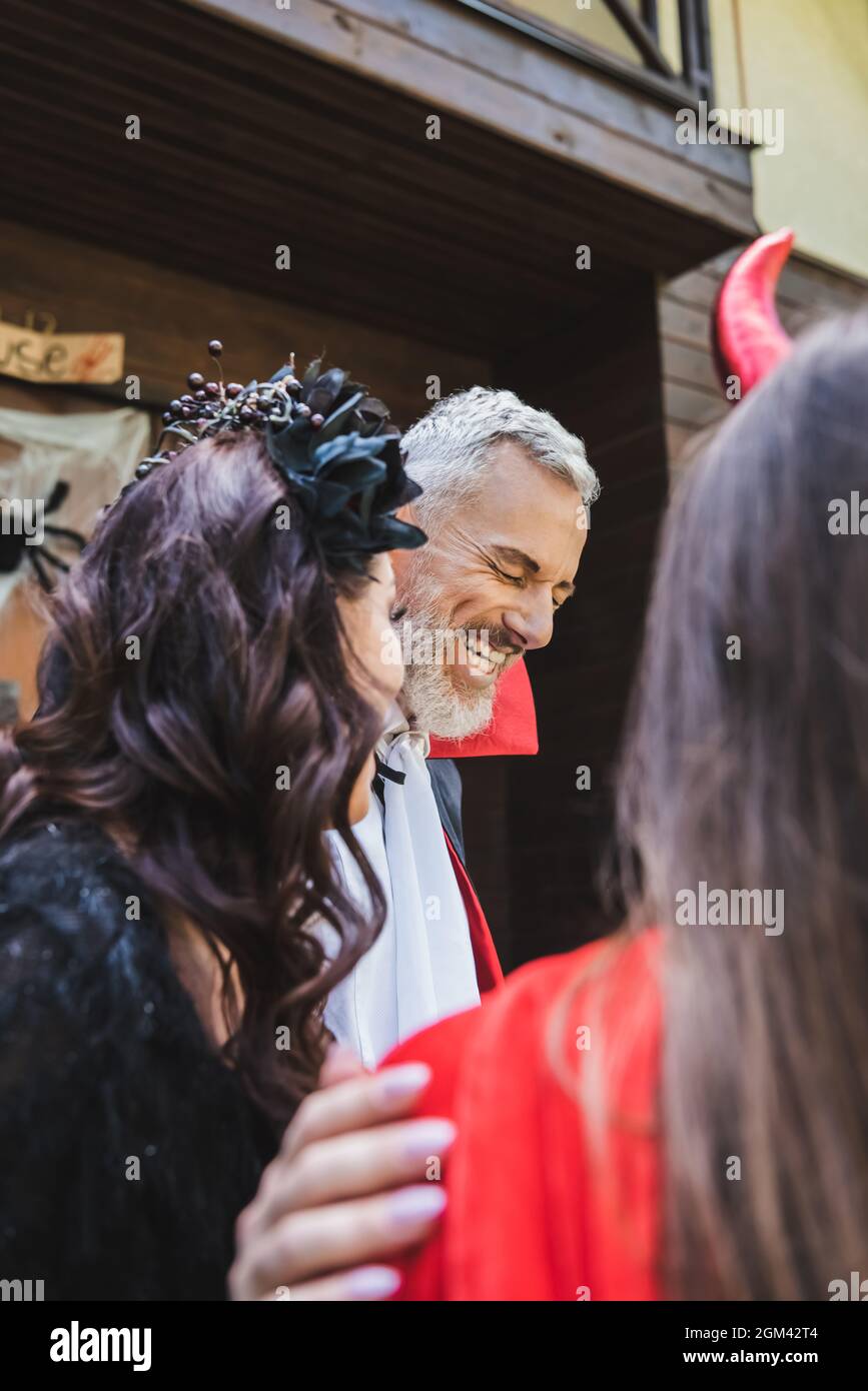excited man laughing with closed eyes near blurred wife and daughter on ...