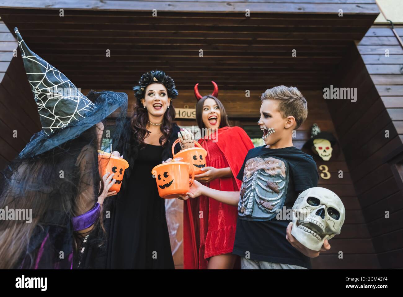 low angle view of excited family in spooky halloween costumes screaming ...