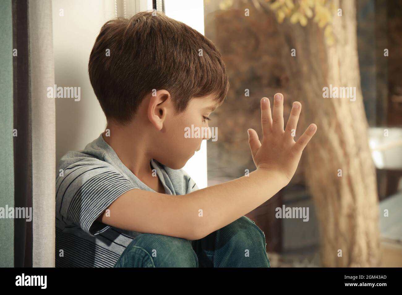 Little sad boy near window. Abuse of children concept Stock Photo - Alamy