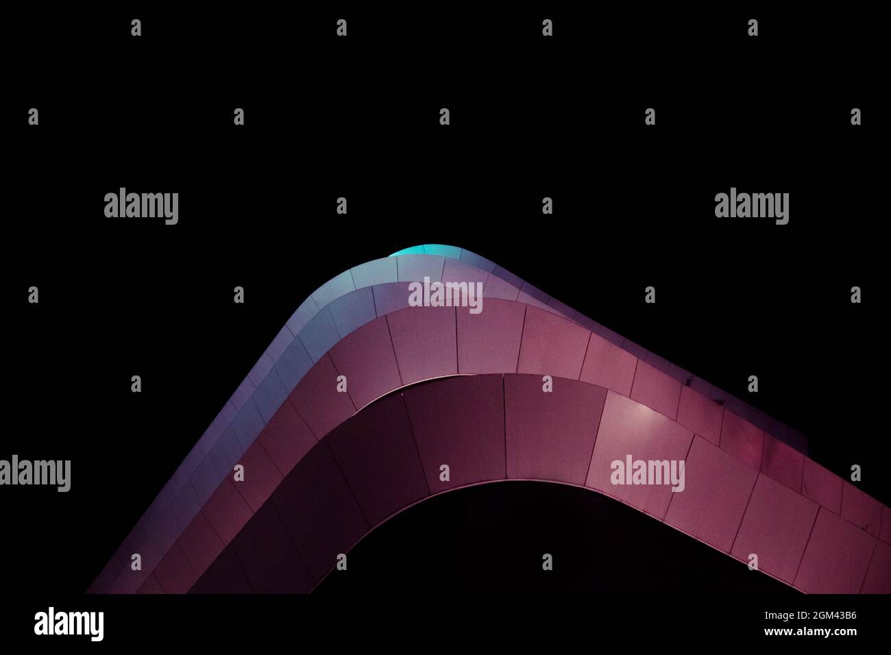 Modern architecture curvy building with led lights at night from bellow ...