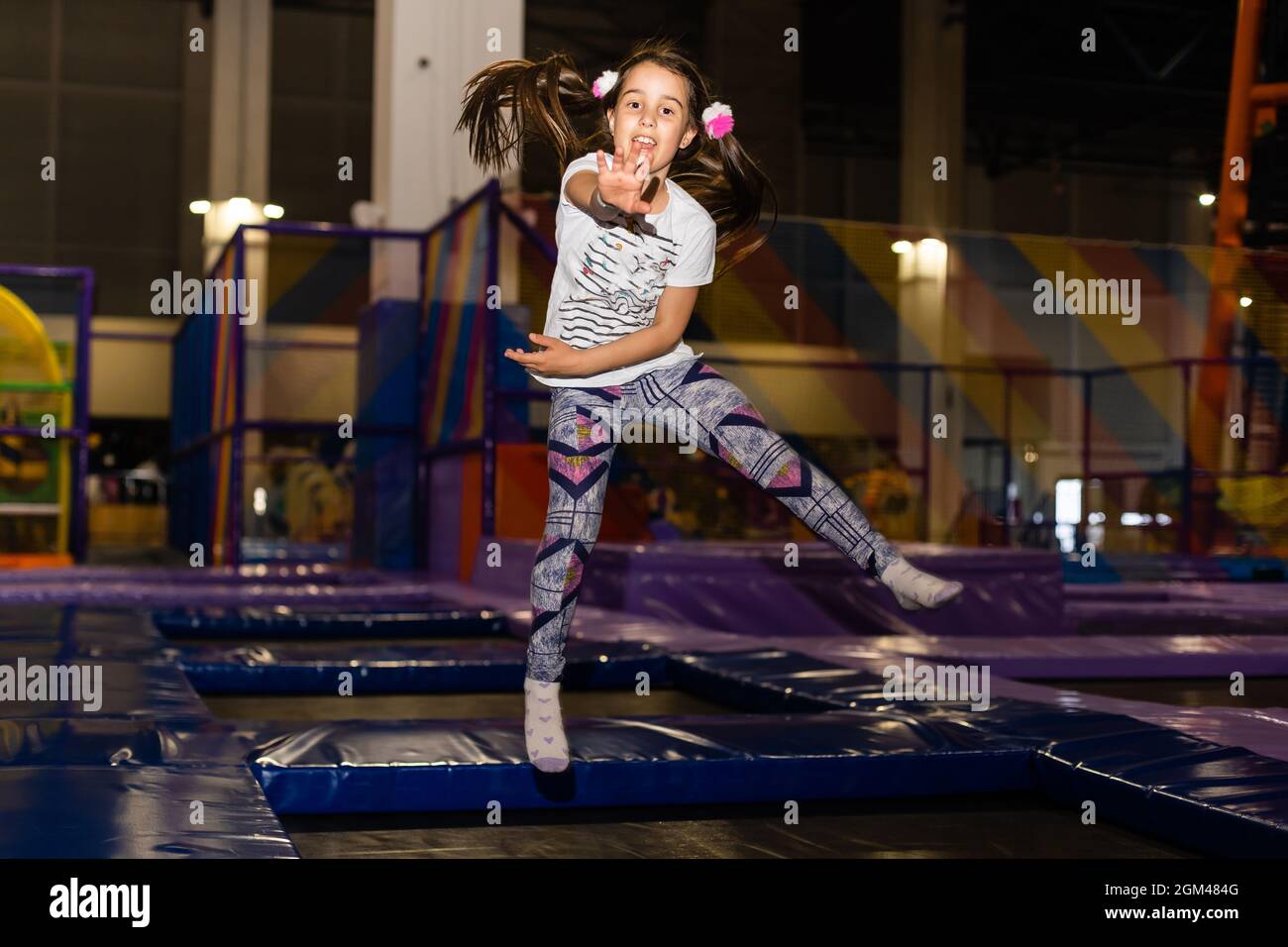 Portrait little cute child girl playing and jumping on trampoline in ...