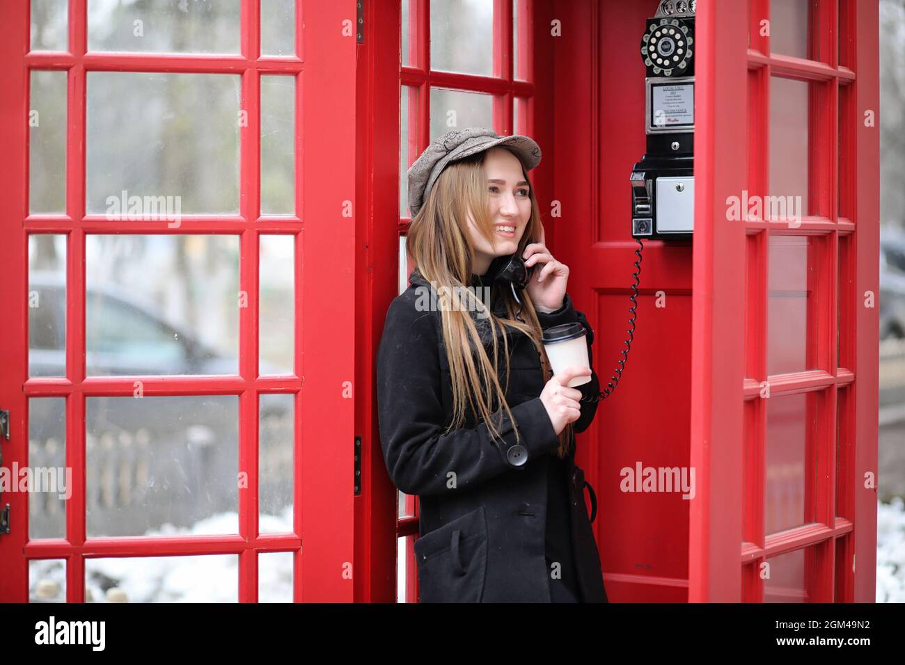 Beautiful young girl in a phone booth. The girl is talking on the phone ...