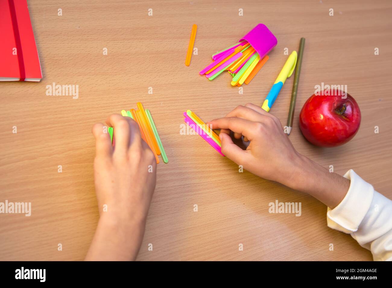 A student at a desk studies math counting with sticks. A schoolboy ...