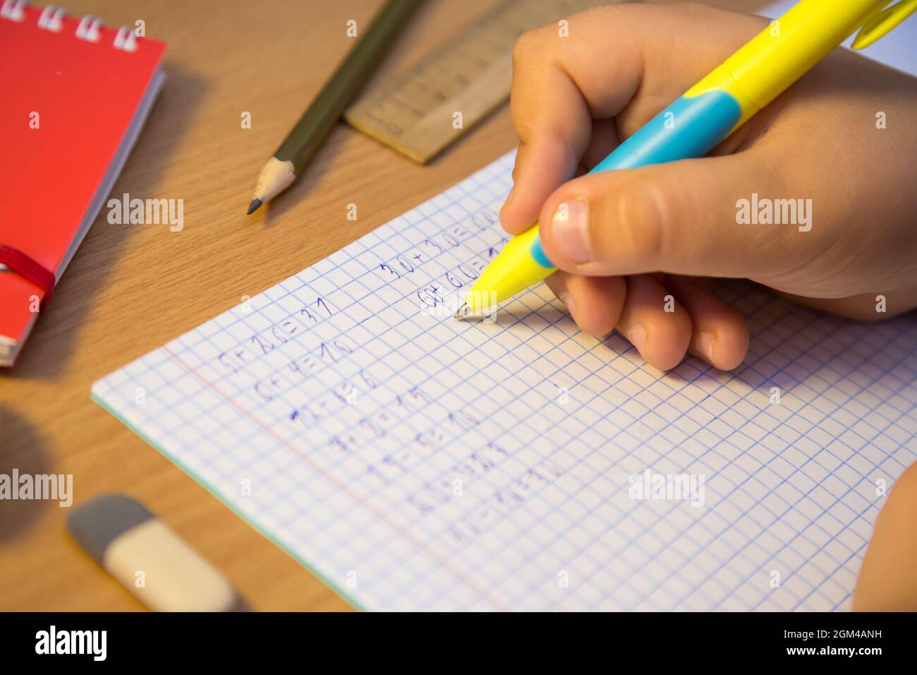 Pupil's hand solves math examples with a ballpoint pen close-up. A ...