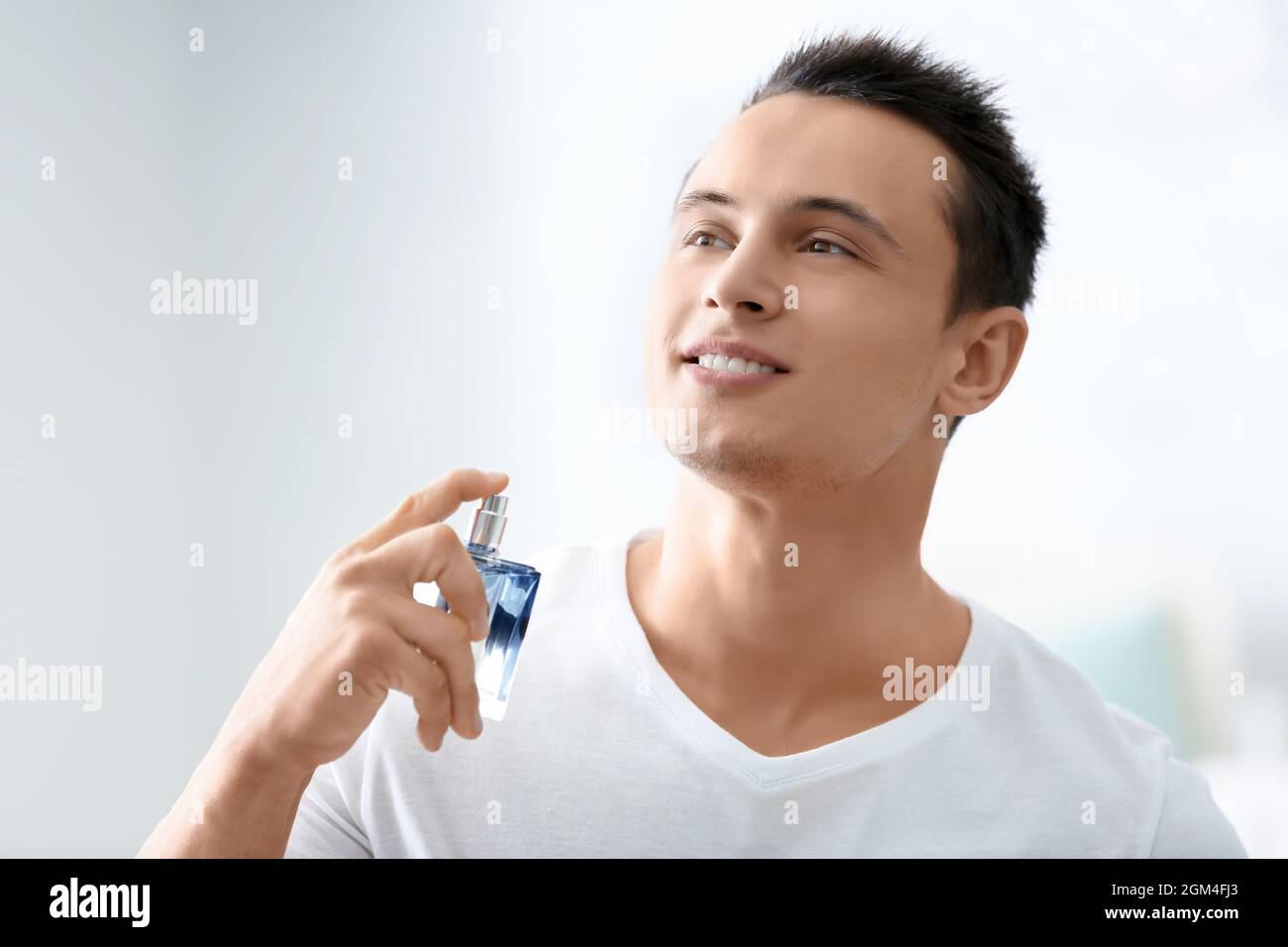Handsome man with bottle of perfume on light background Stock Photo - Alamy