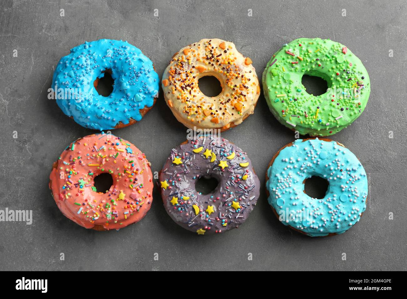 Colorful donuts with sprinkles on grey background Stock Photo - Alamy