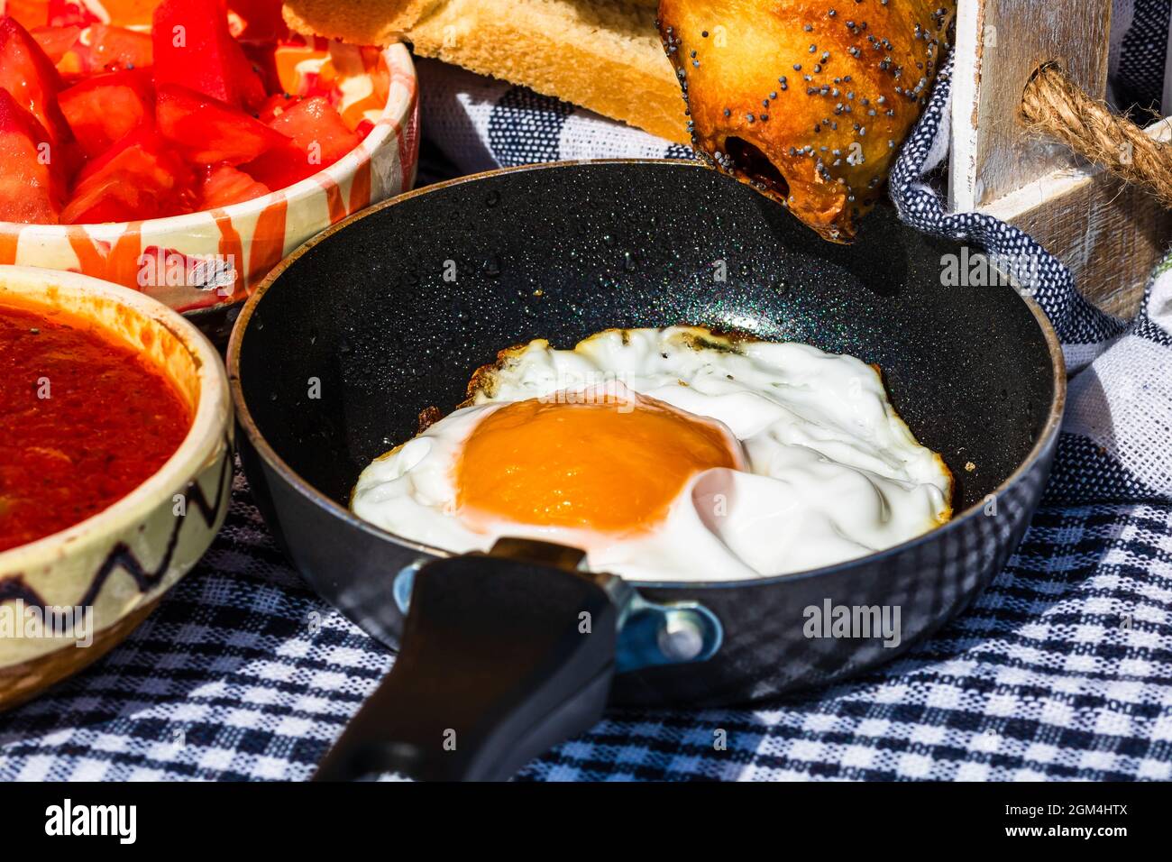 Closeup of a fried egg in a small frying pan in a rustic composition ...